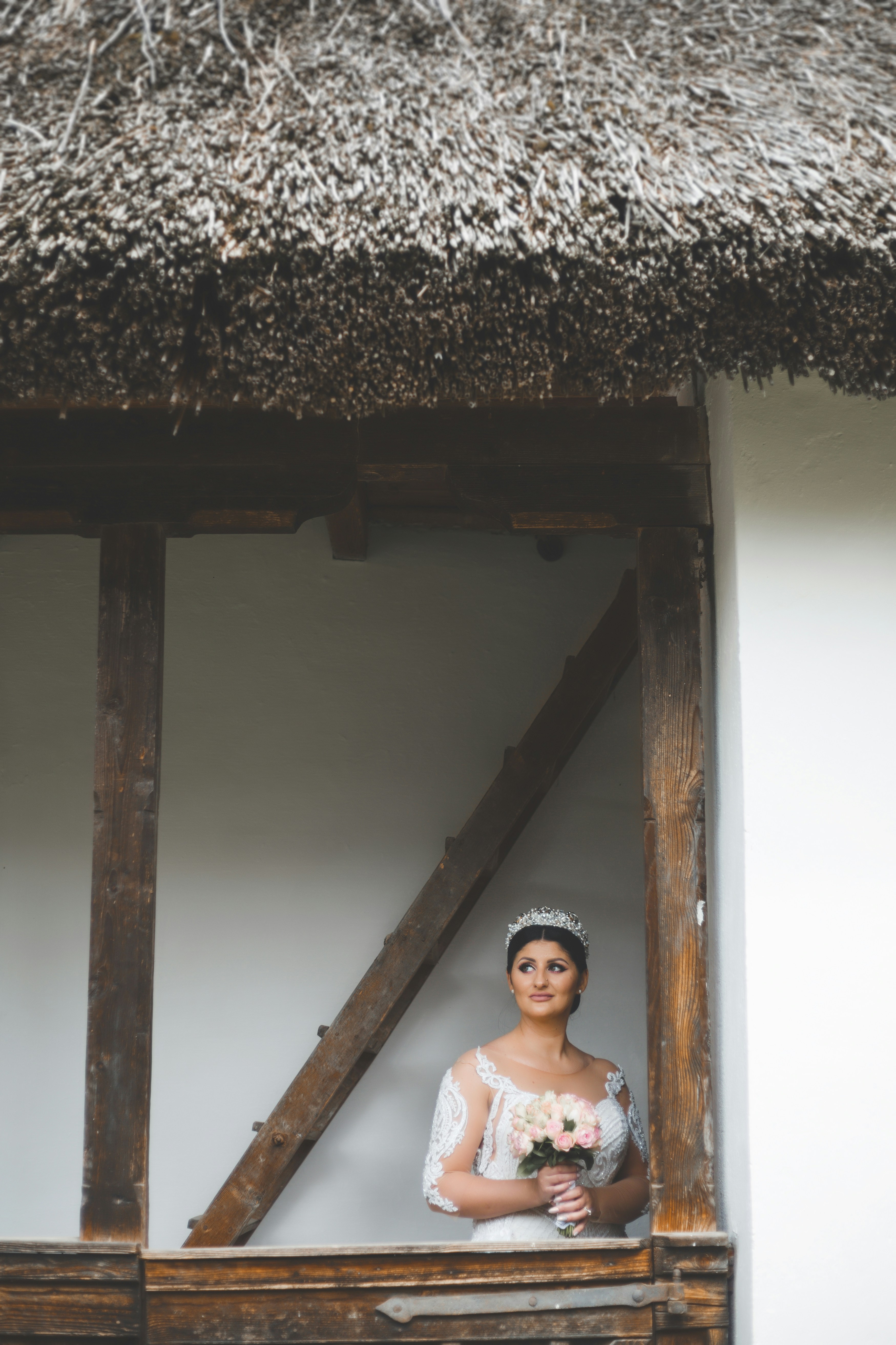 Rustic doorway bridal portrait beneath a thatched canopy