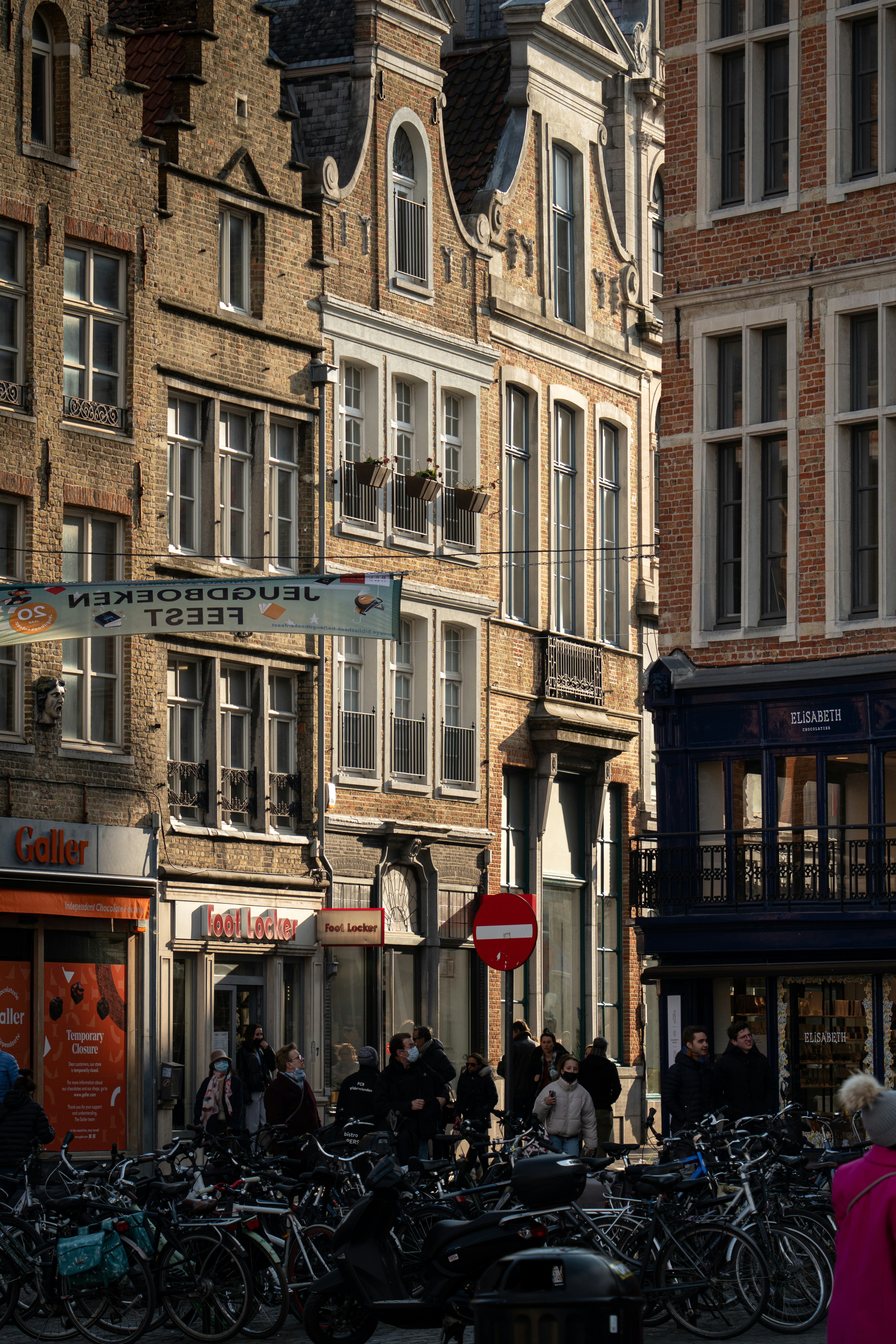 Historic buildings framed by modern life, with bicycles and pedestrians populating the street scene. A vibrant urban environment in motion.