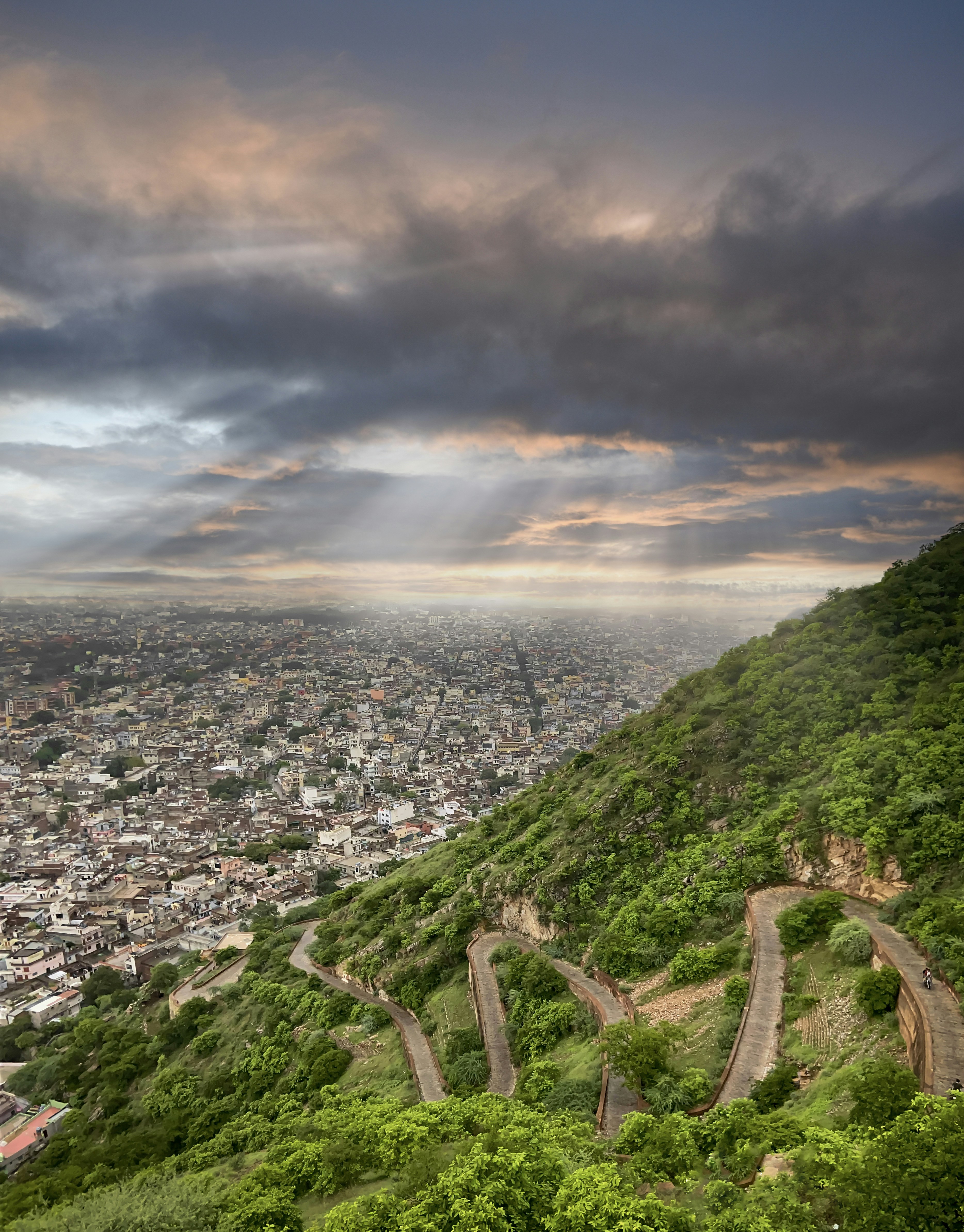 Winding Summit Road Through a Verdant Ridge Overlooking a City
