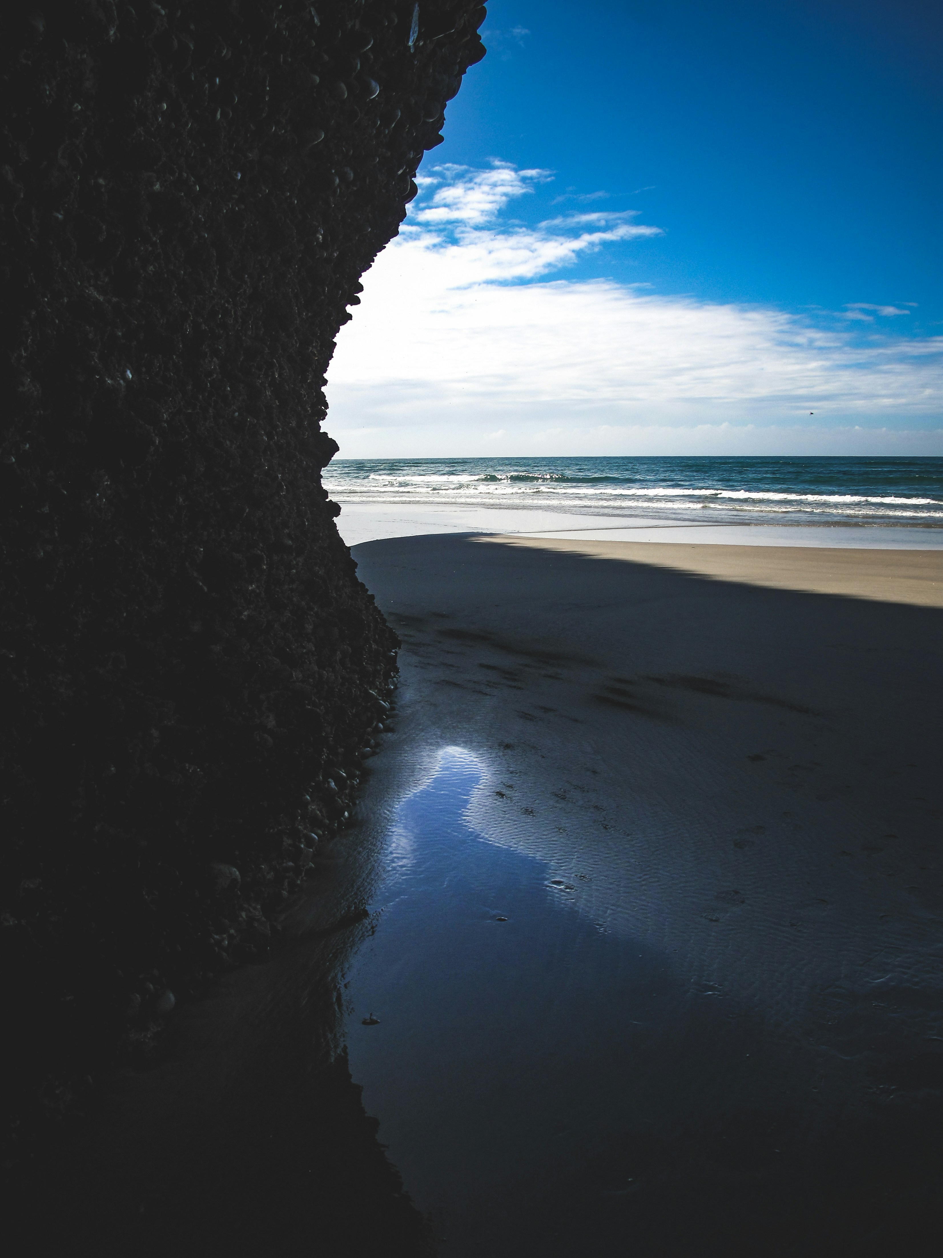 A view of a beach through a crack in a rock photo – Free Blue Image on ...