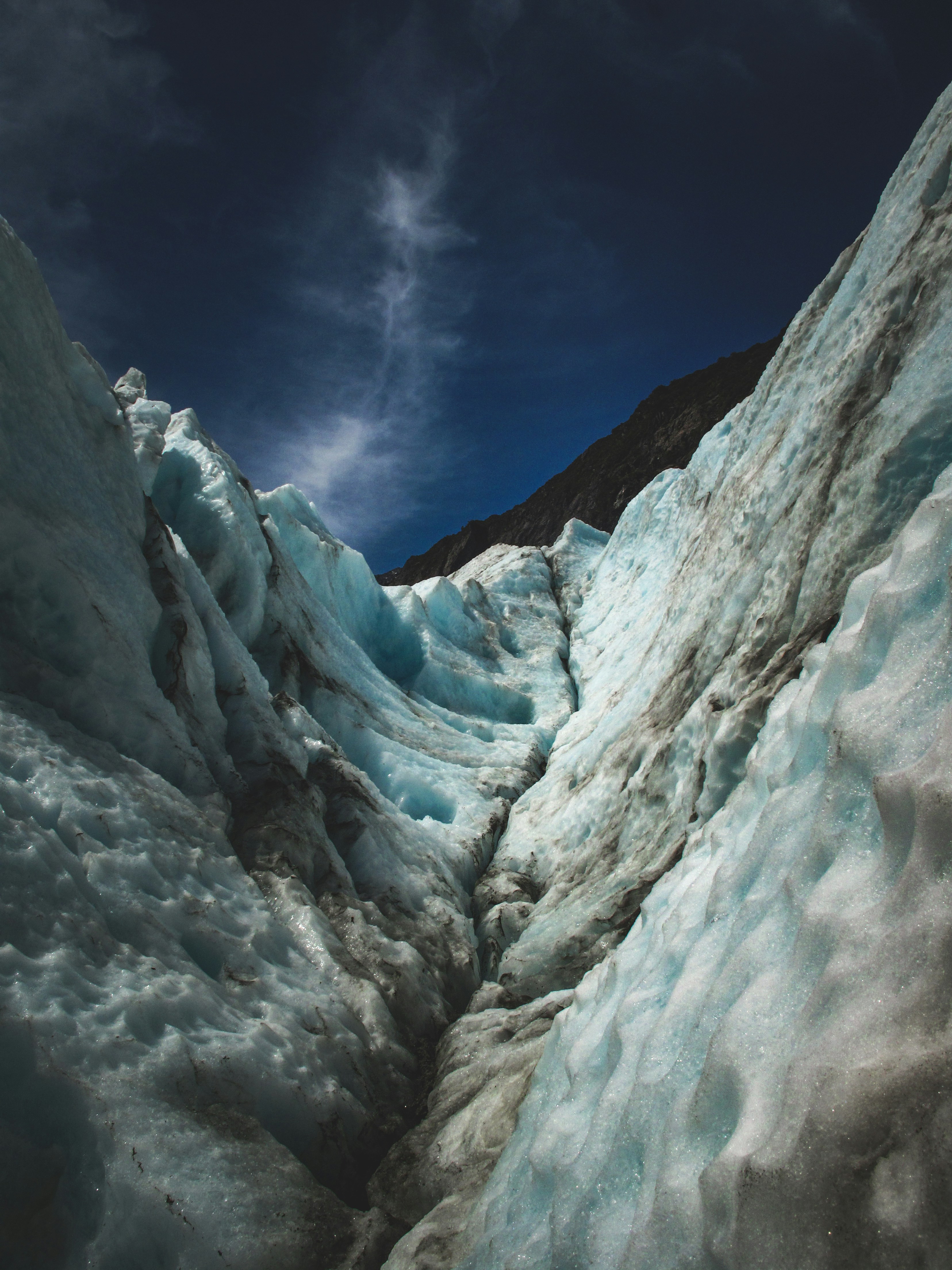 Glacial formations create a winding pathway through a deep icy canyon under a dramatic sky.