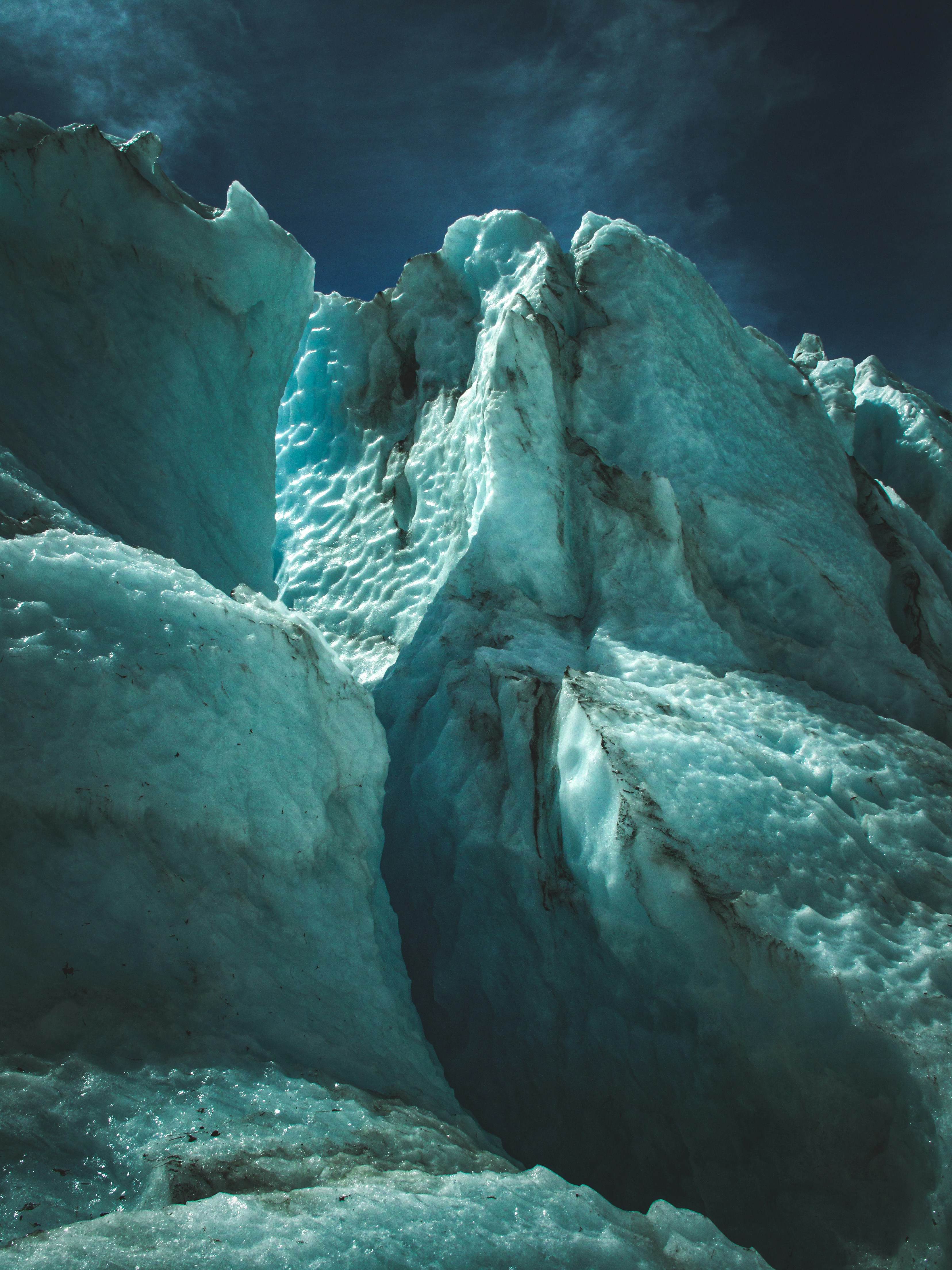Jagged ice formations rise dramatically against a dark sky, showcasing the intricate textures and hues of glacial ice.