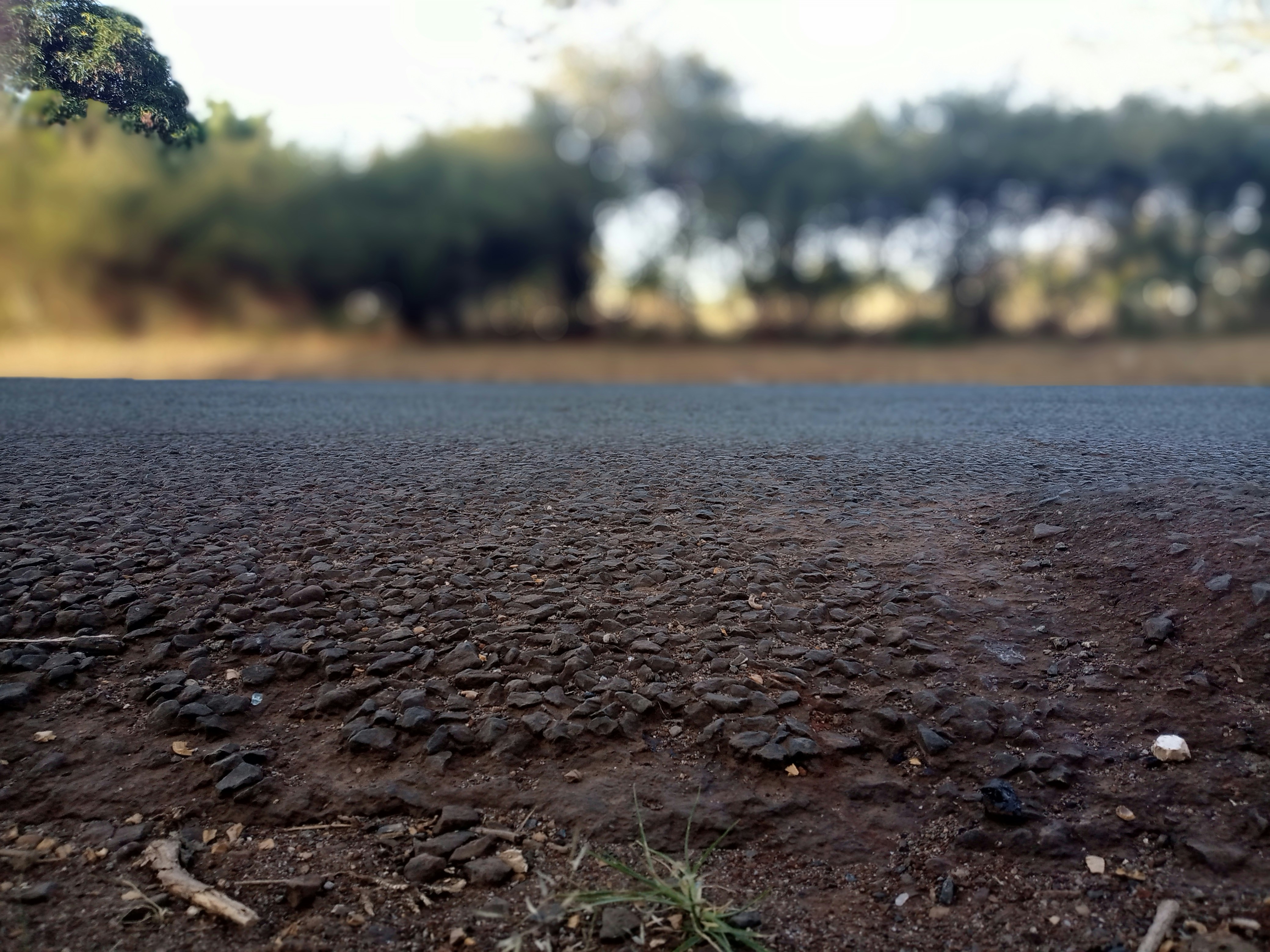 Ground-Level Mosaic: Gravel, Asphalt, and a Soft Horizon