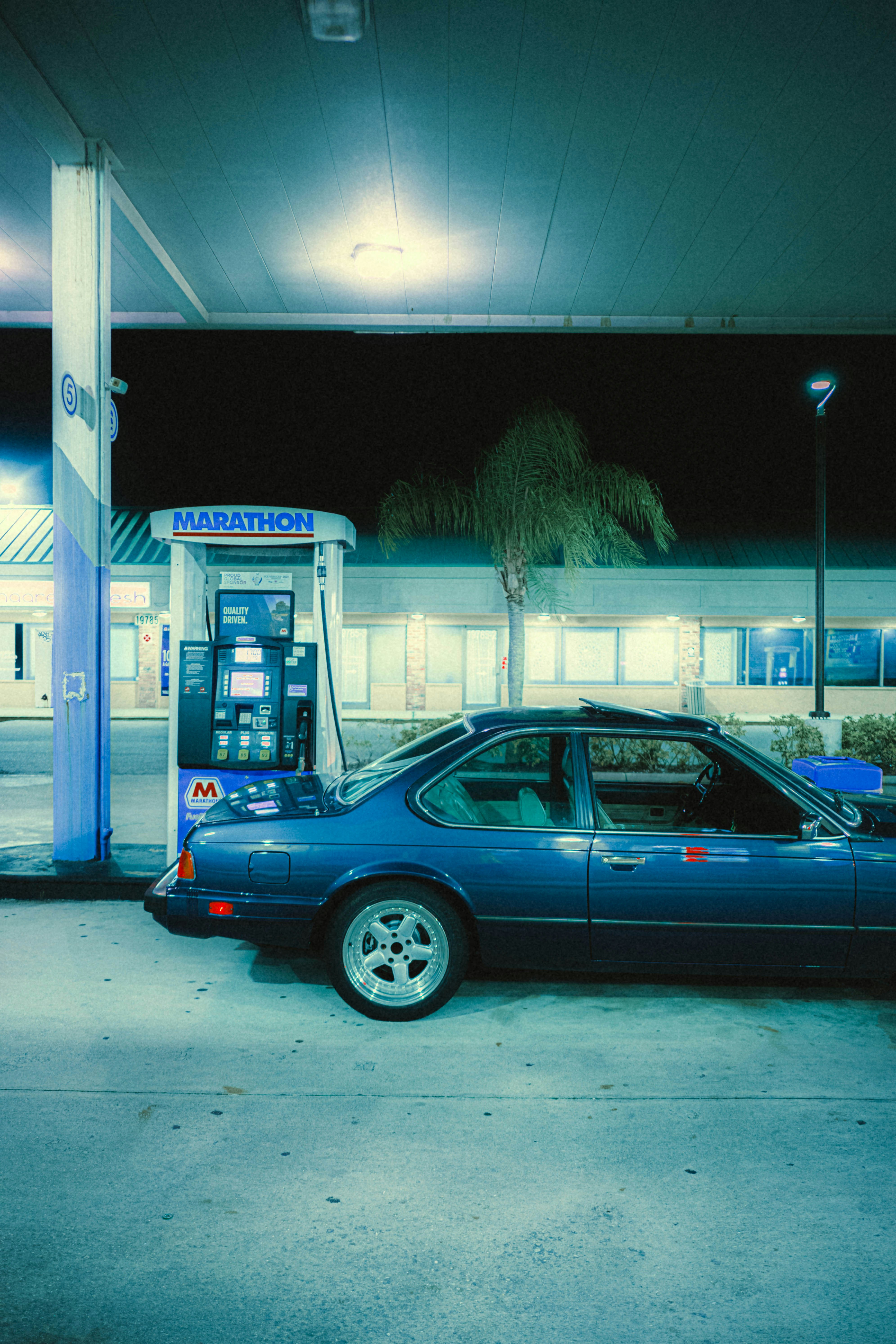Neon Quiet at Marathon: A Vintage Blue Coupe Under Fluorescent Night