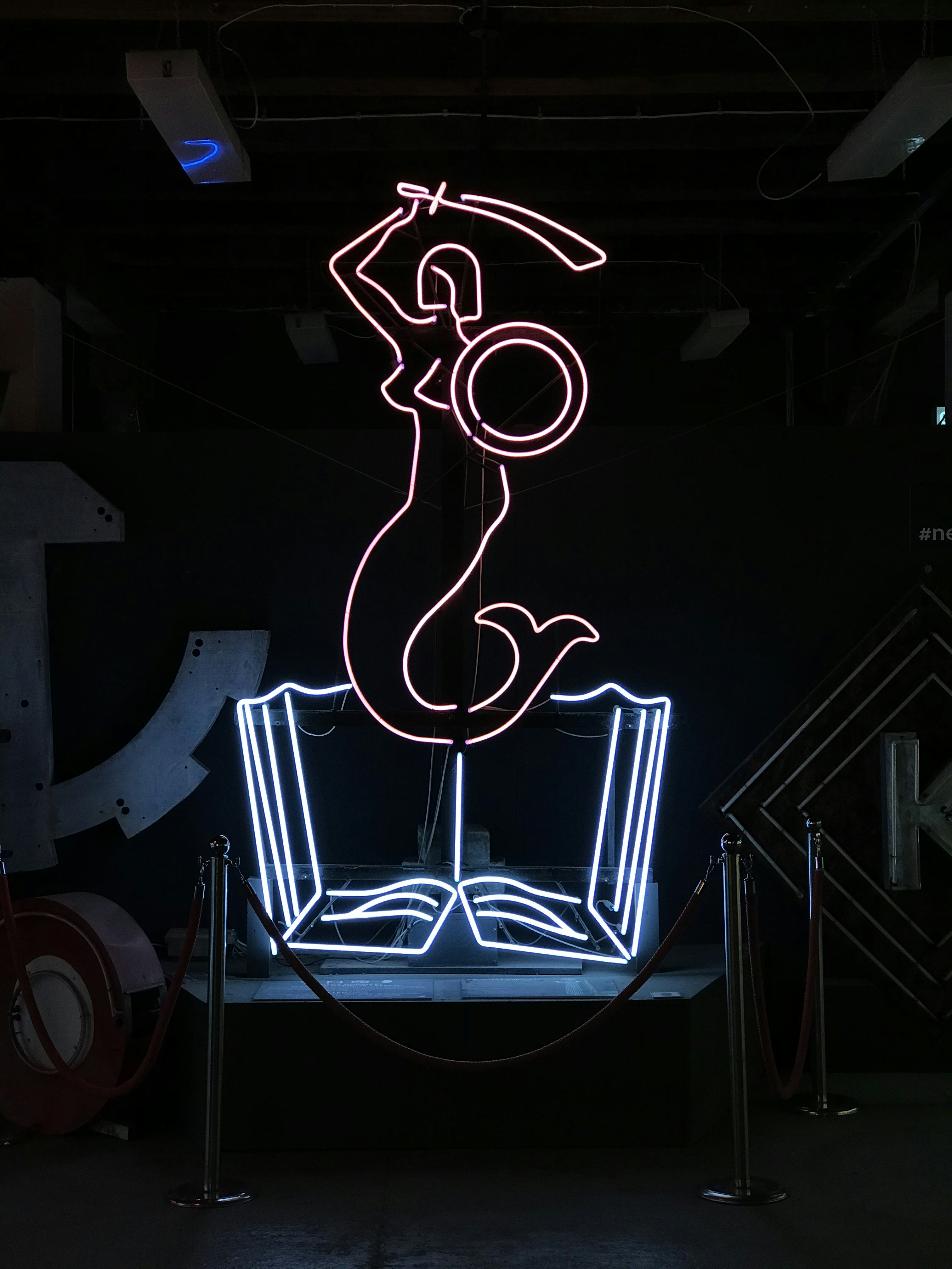 Neon Silhouette Afloat: A Fluid Figure Rising from an Open-Book Lightscape