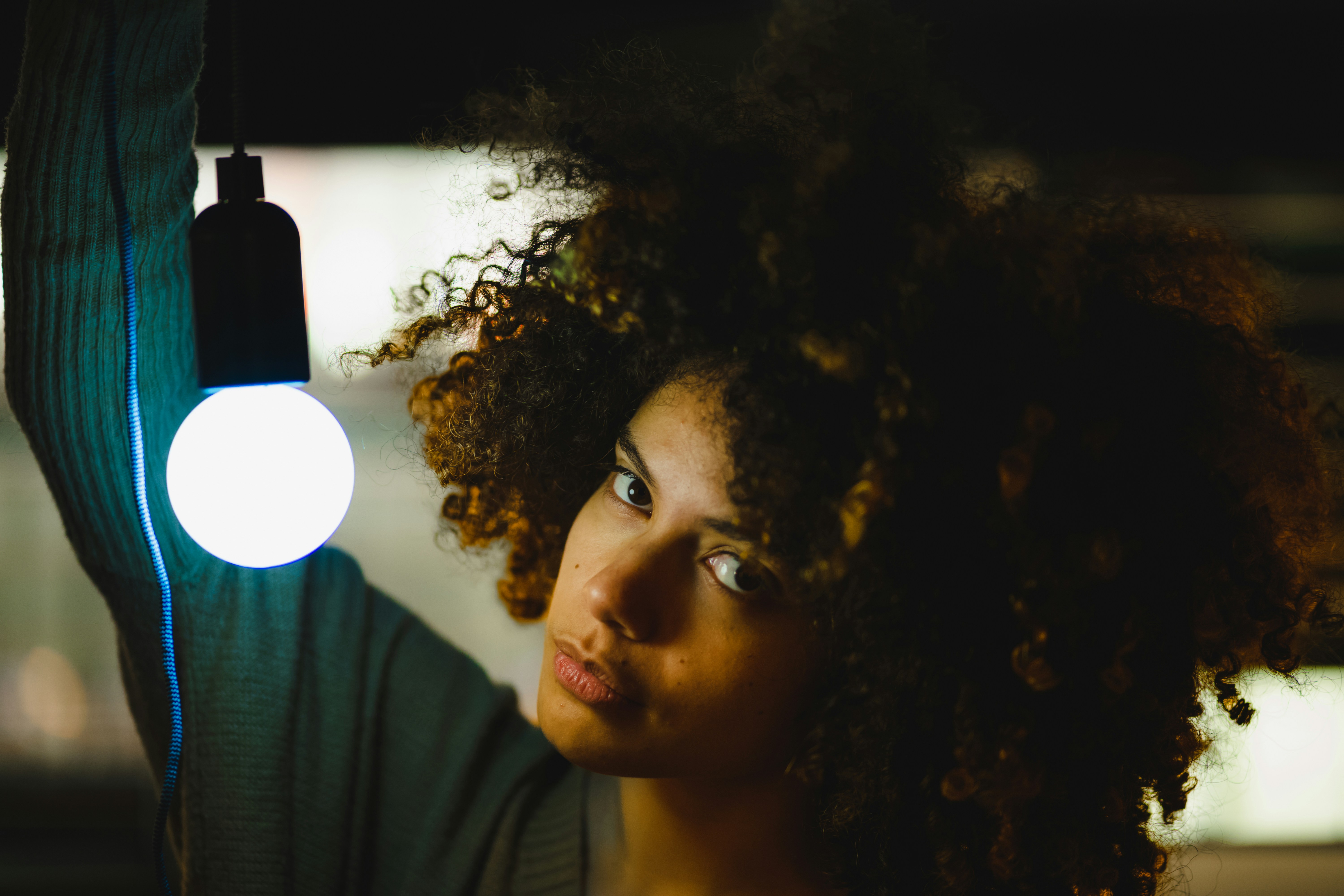 A woman with curly hair holding a light bulb photo – Free Hair Image on ...