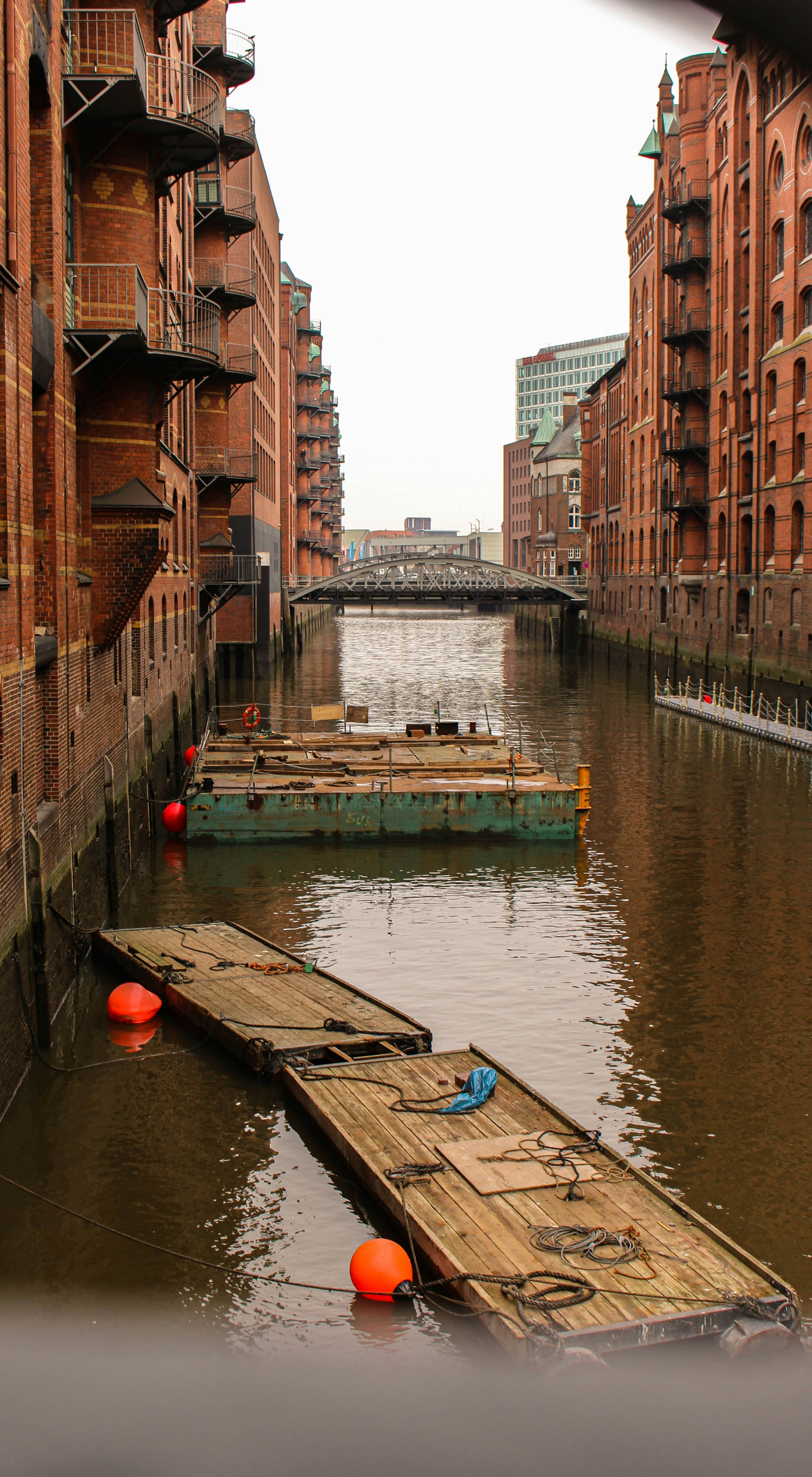 Industrial canal corridor framed by brick warehouses and drifting barges
