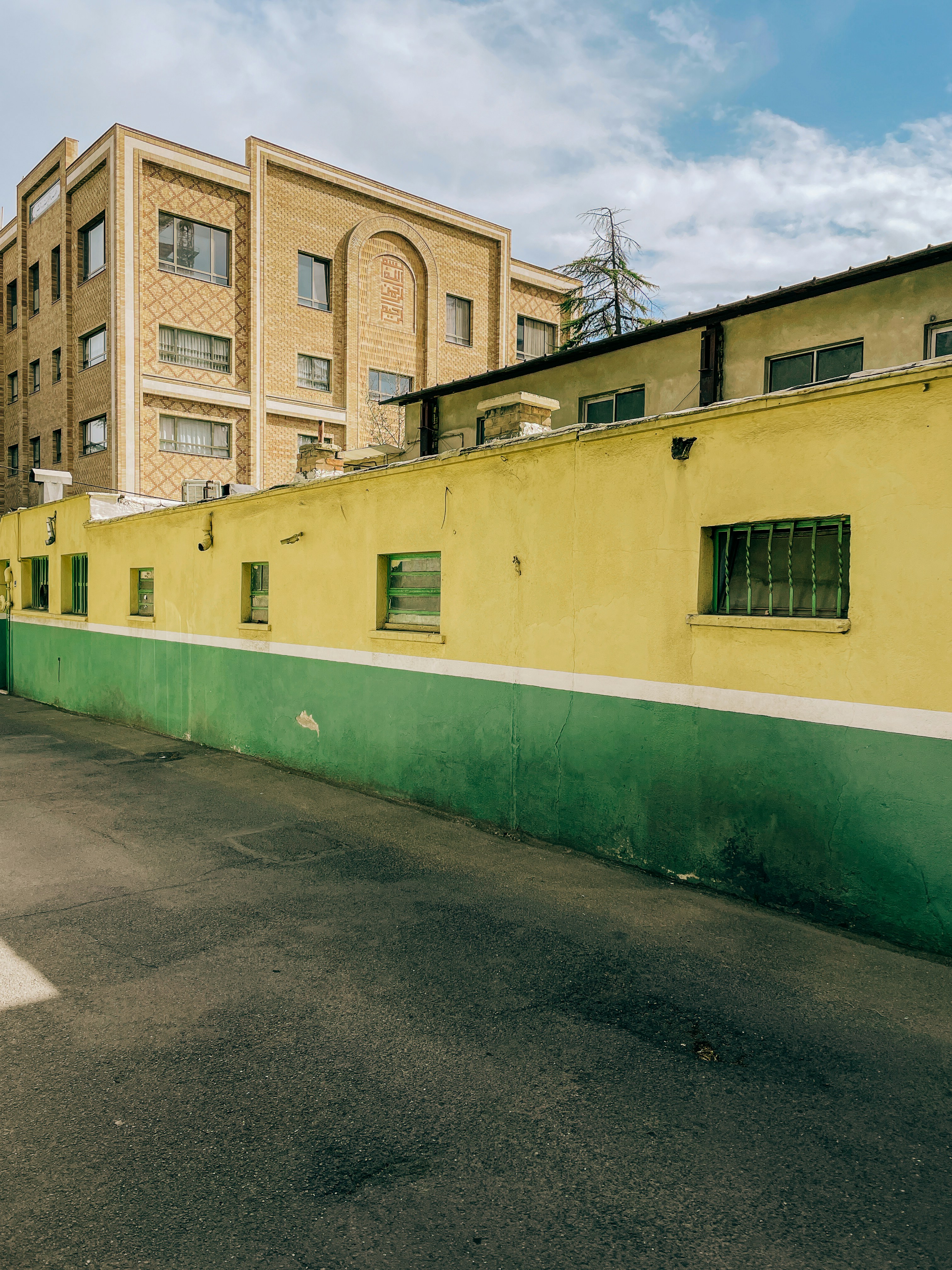Sunlit Yellow Wall Framing a Brick-Backed Urban Corner