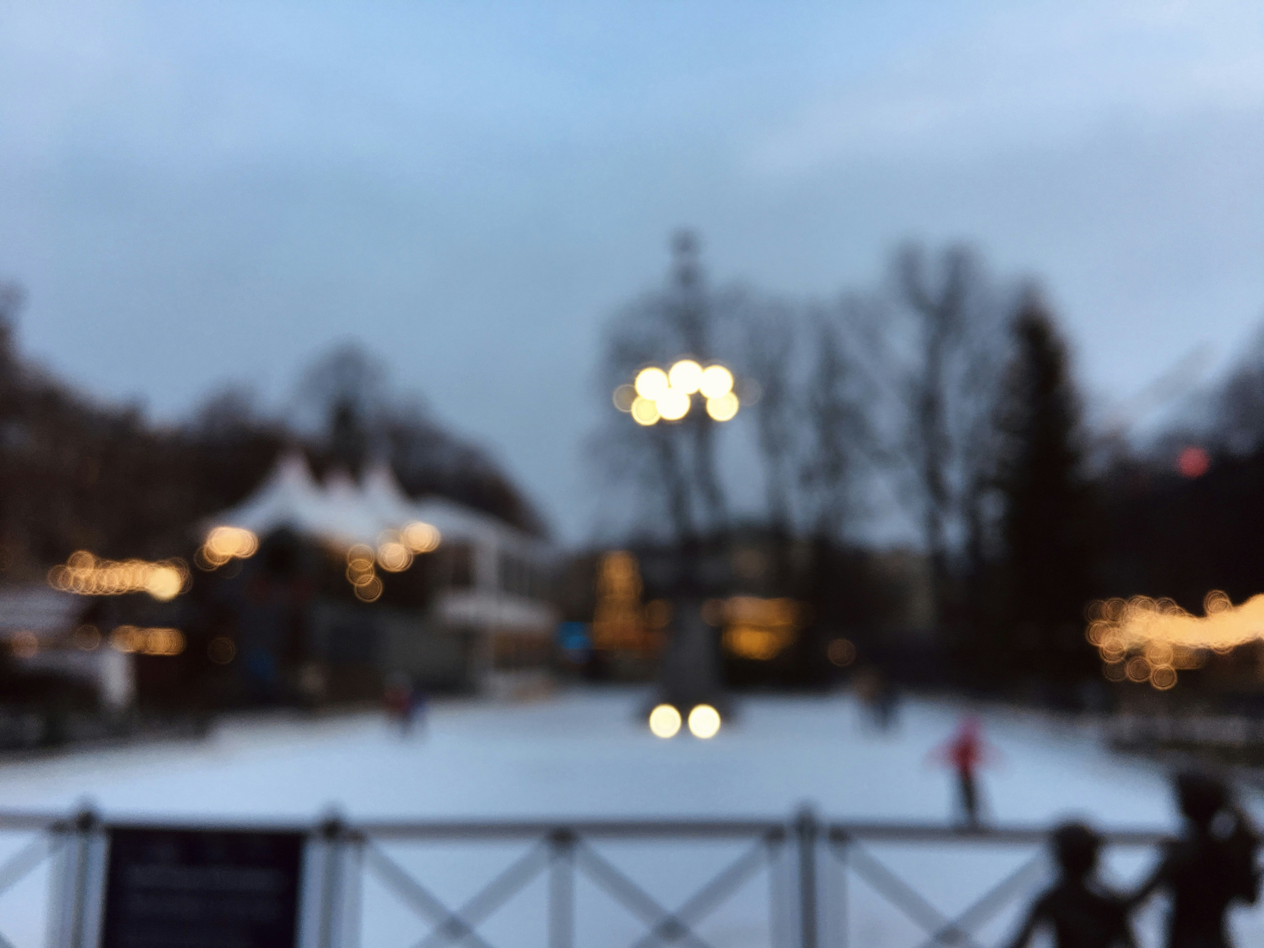 Blurred scene of an ice skating rink adorned with festive lights, capturing the essence of a winter gathering.