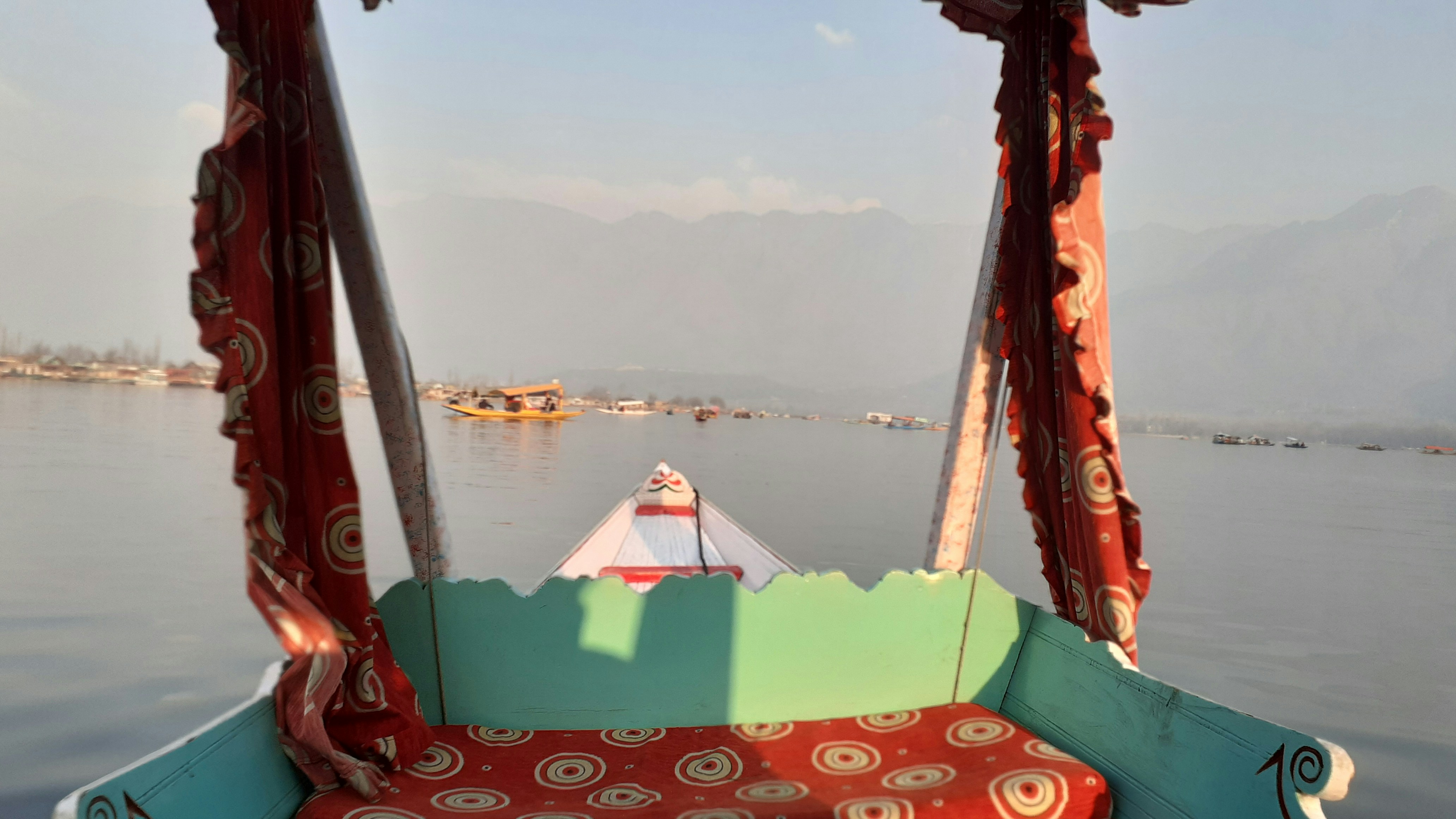 Boat with red and green seats glides on calm waters under a clear sky.