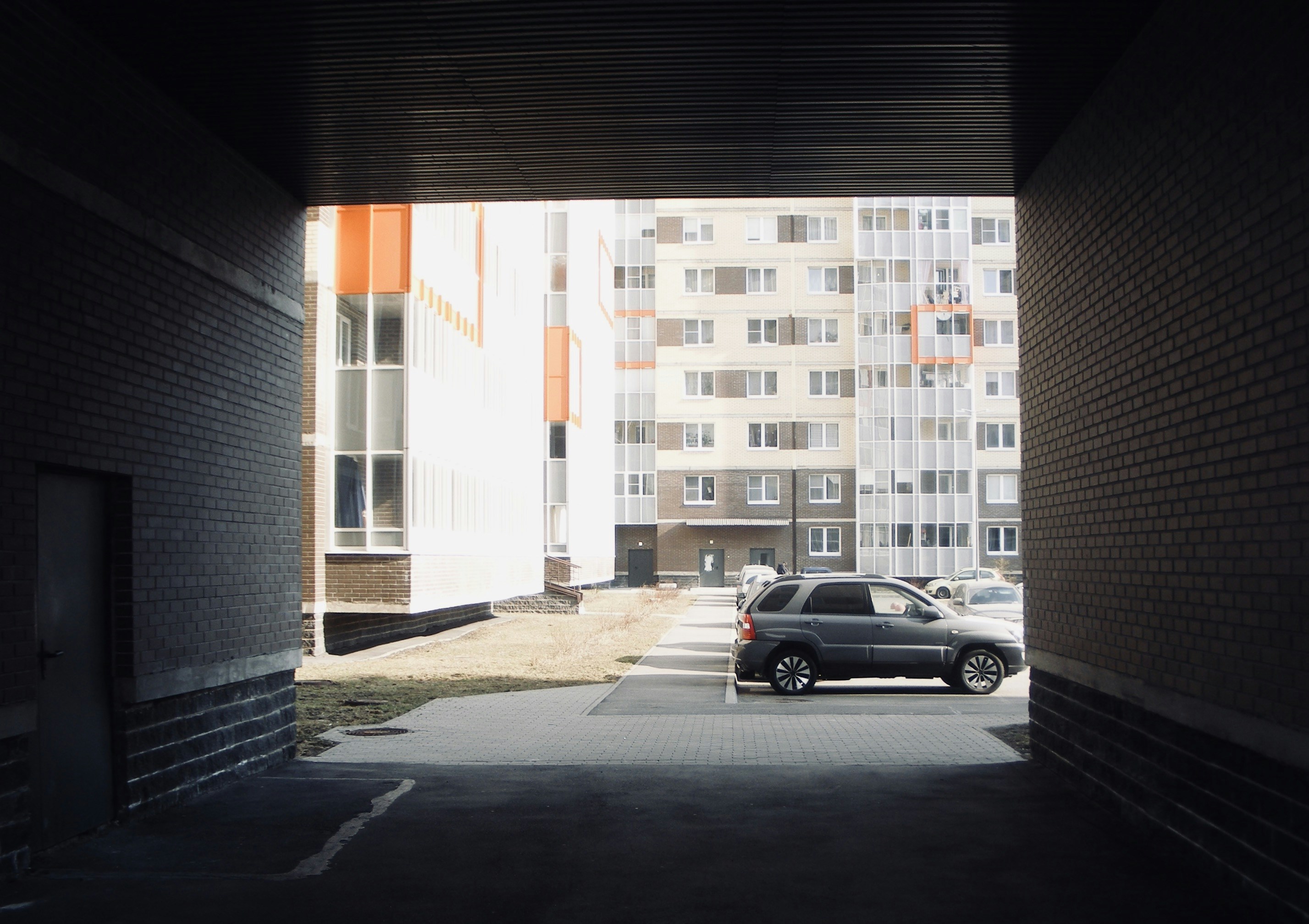 Threshold of Light: Car at the Exit of a Sunlit Courtyard
