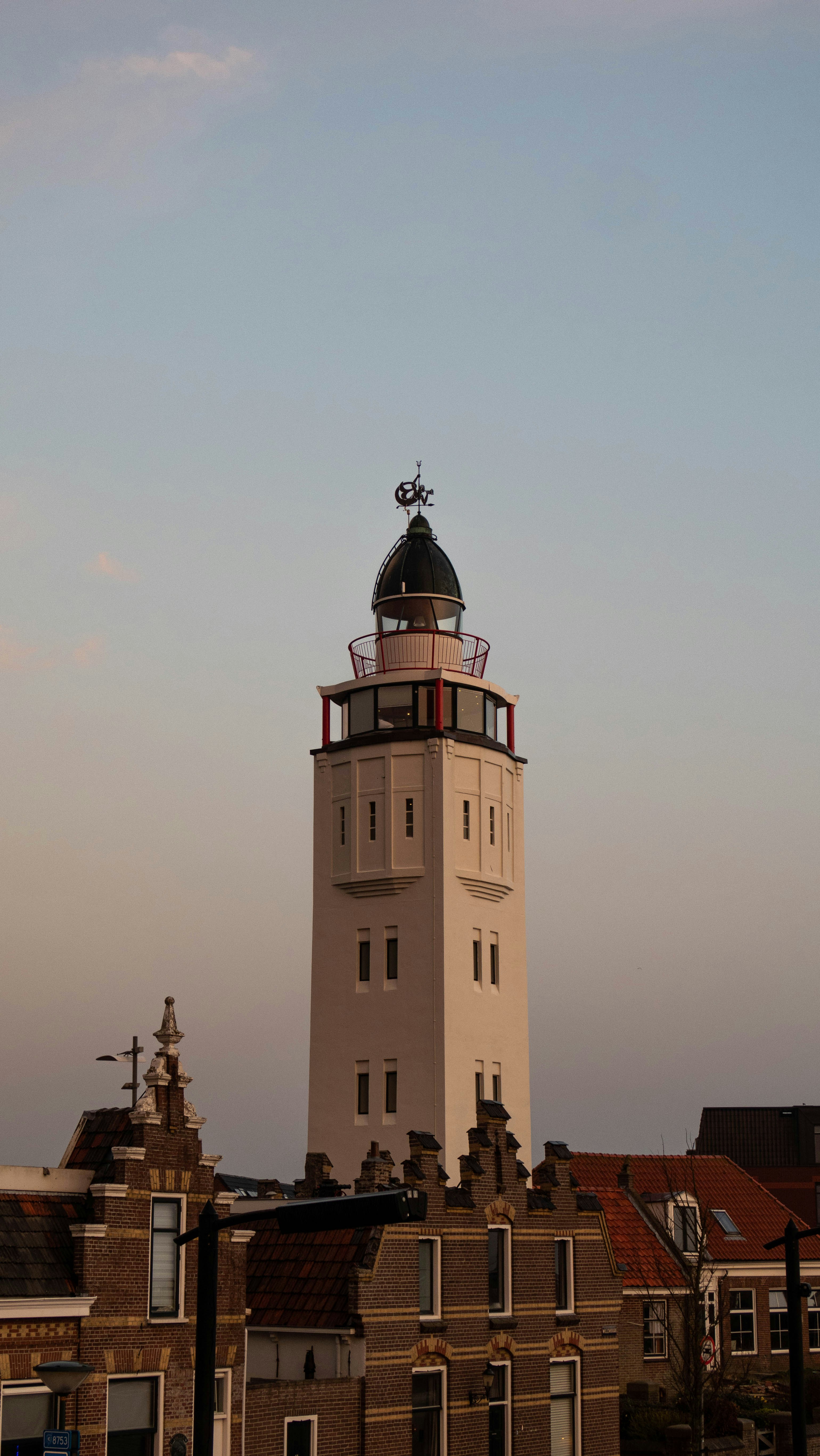 Historic lighthouse standing tall against a pastel sky, surrounded by charming architecture. A symbol of maritime guidance.