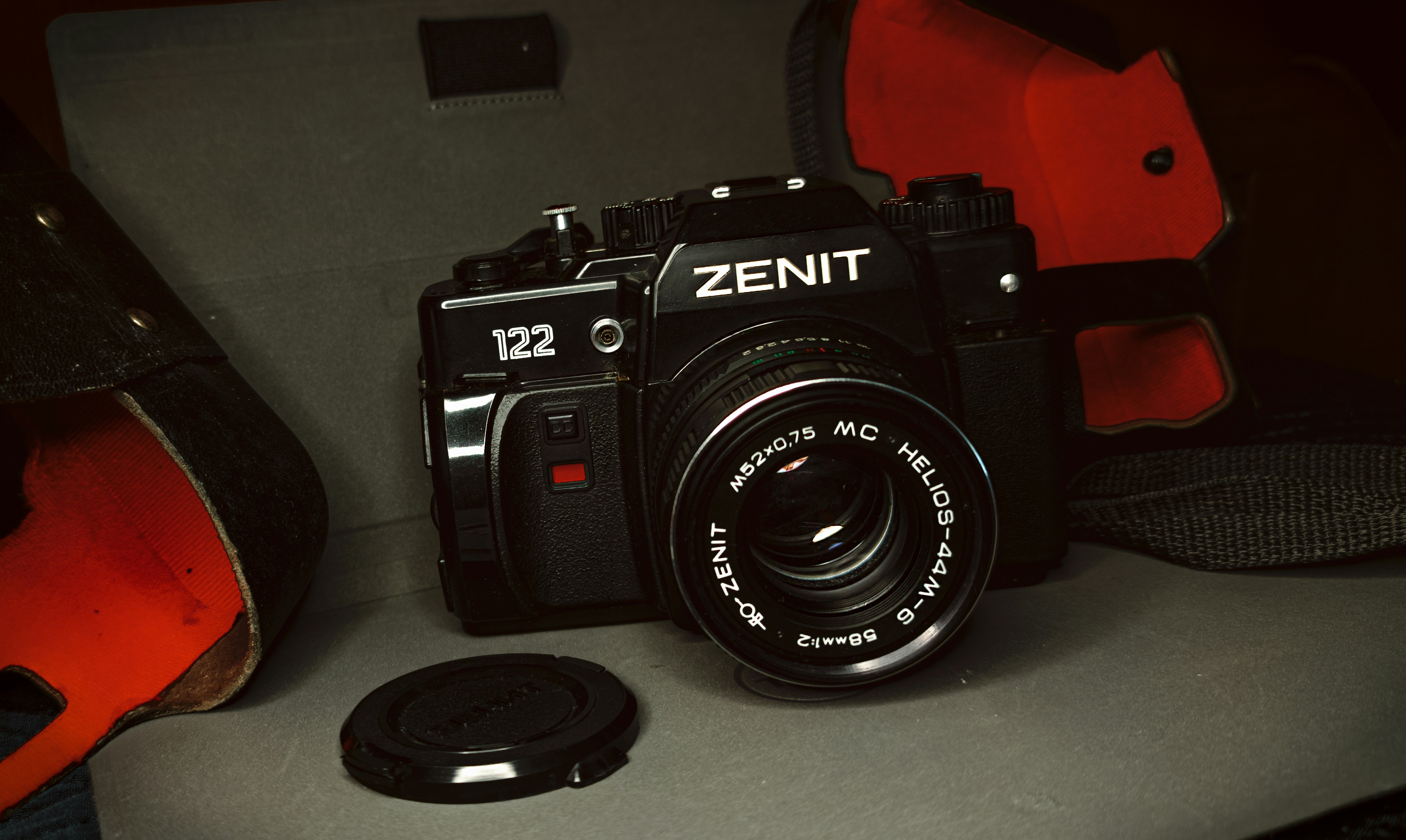 Zenit 122 camera positioned on a textured surface with accessories, showcasing its vintage design and craftsmanship.