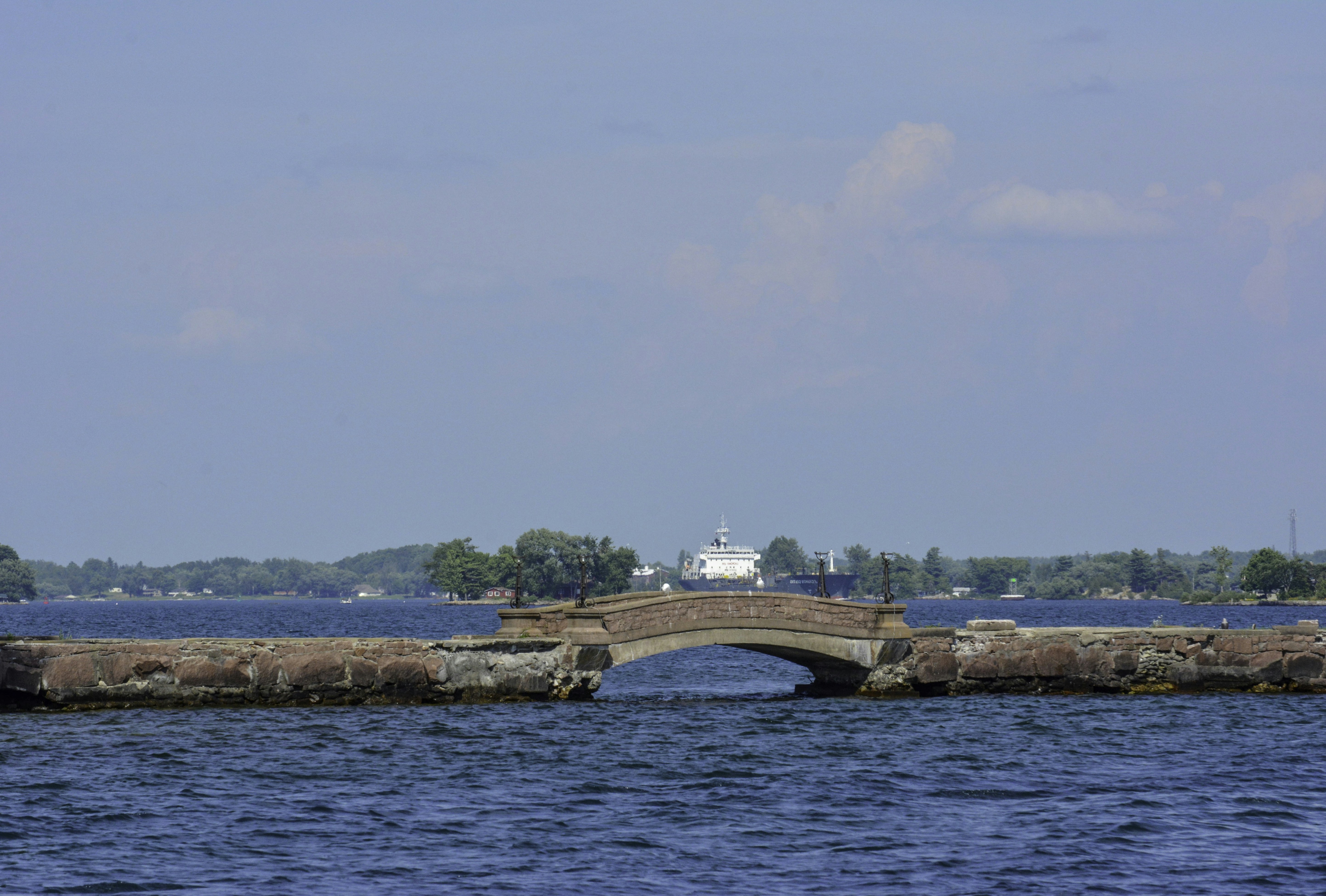 A bridge over a body of water with a boat in the background photo ...