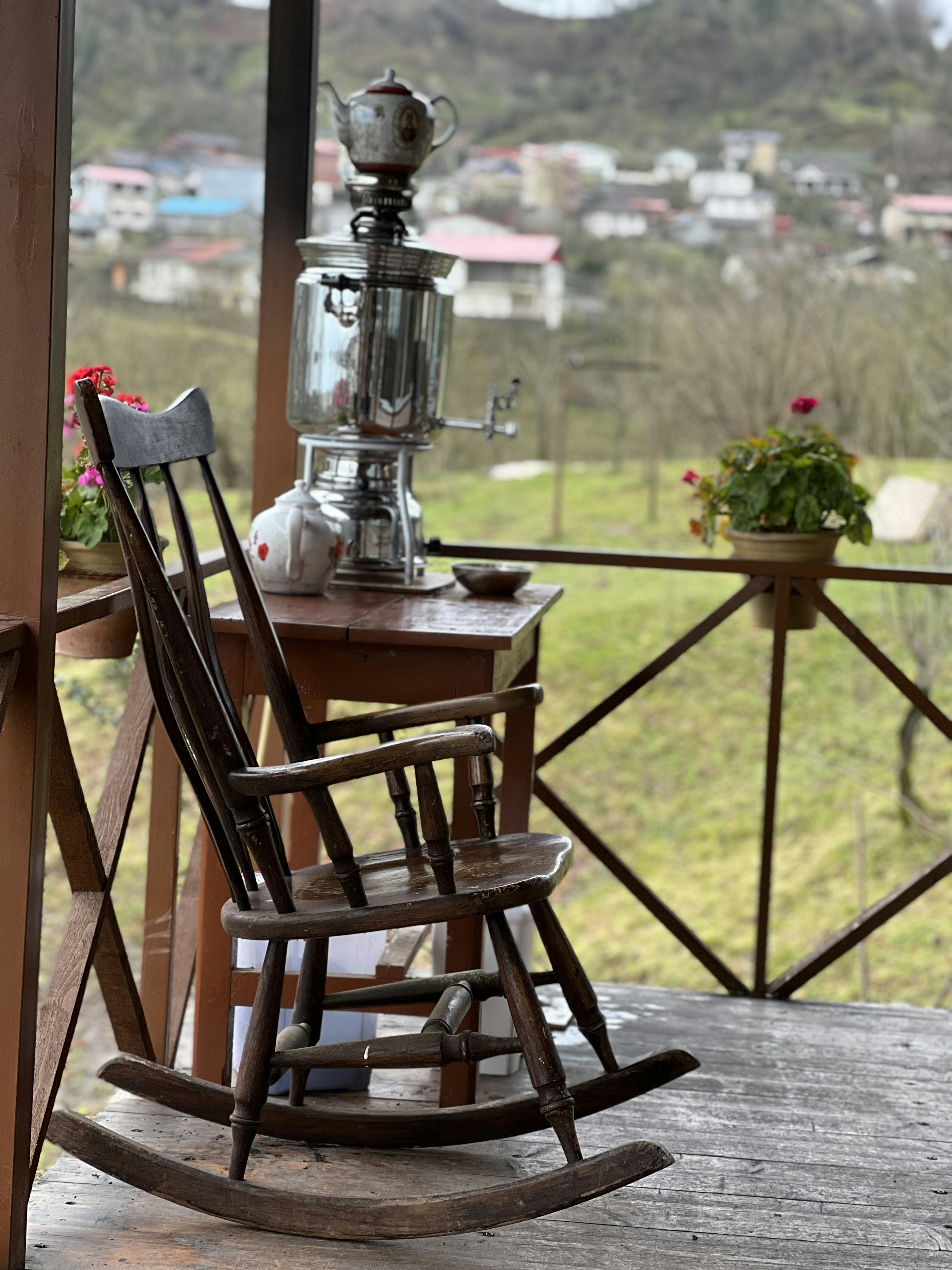 Rustic Rocking Chair on a Porch Framing a Hilly Village View