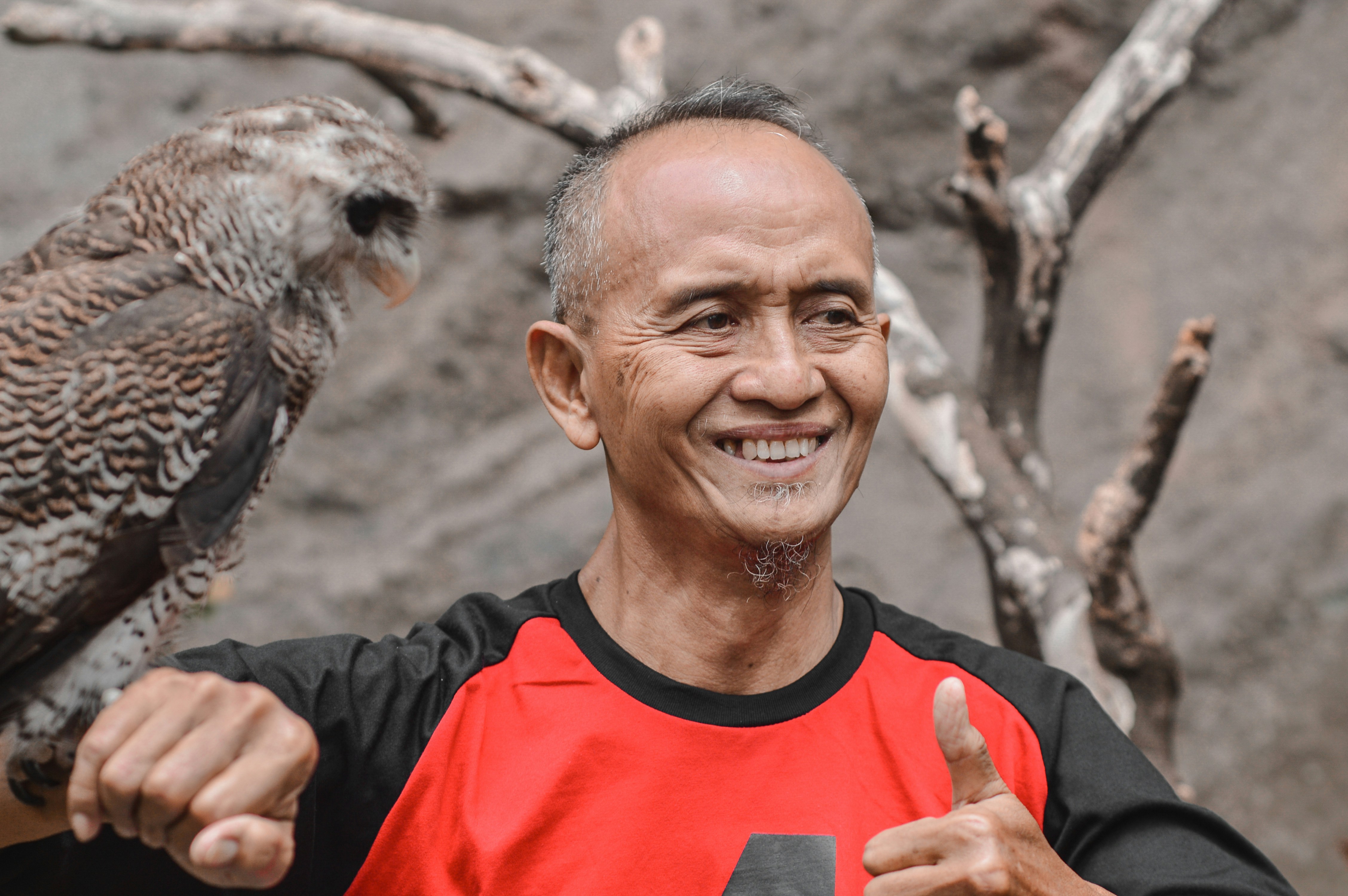 a man giving a thumbs up with an owl on his arm