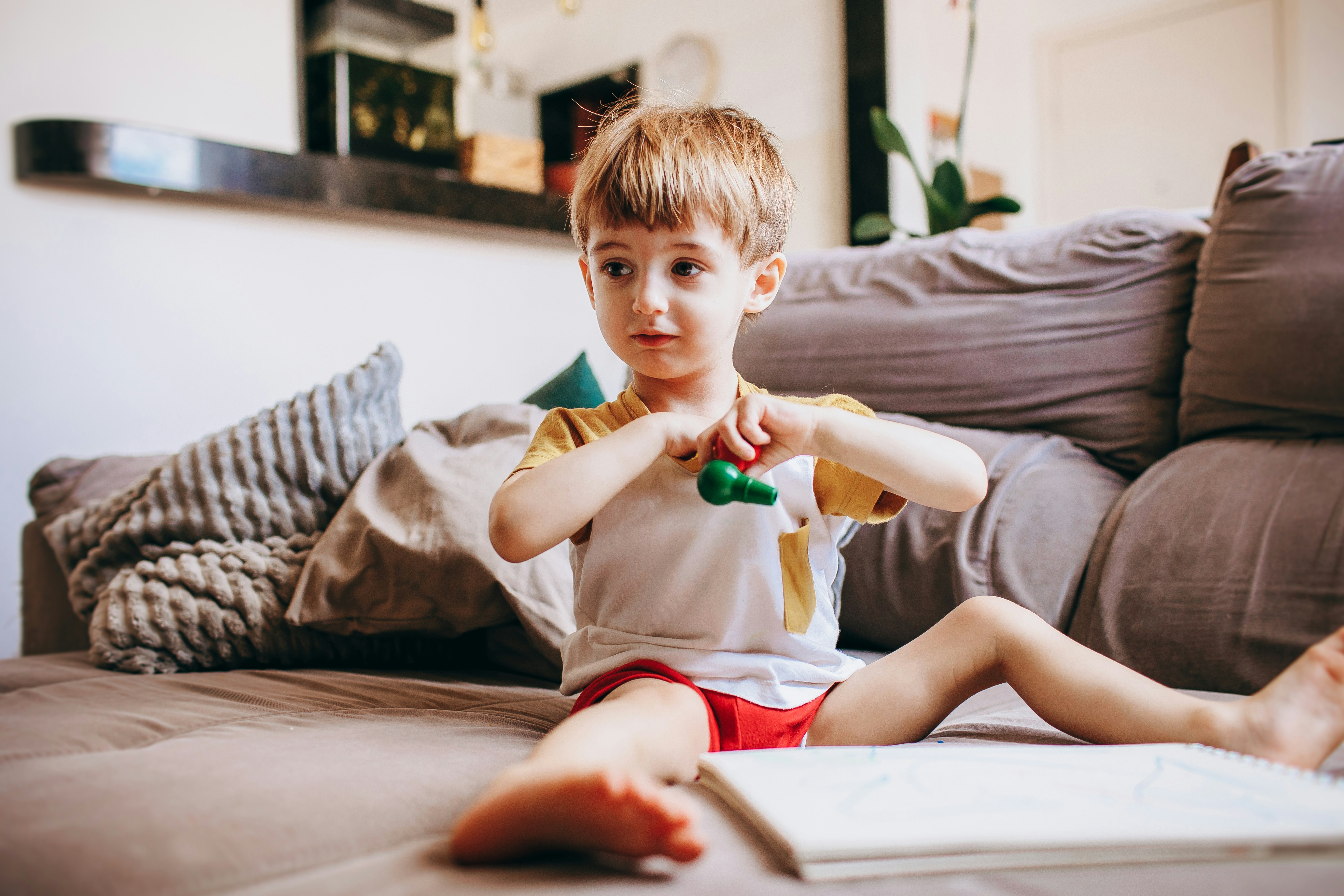 Foto Un niño sentado en el suelo jugando con un juguete – Imagen Gris ...