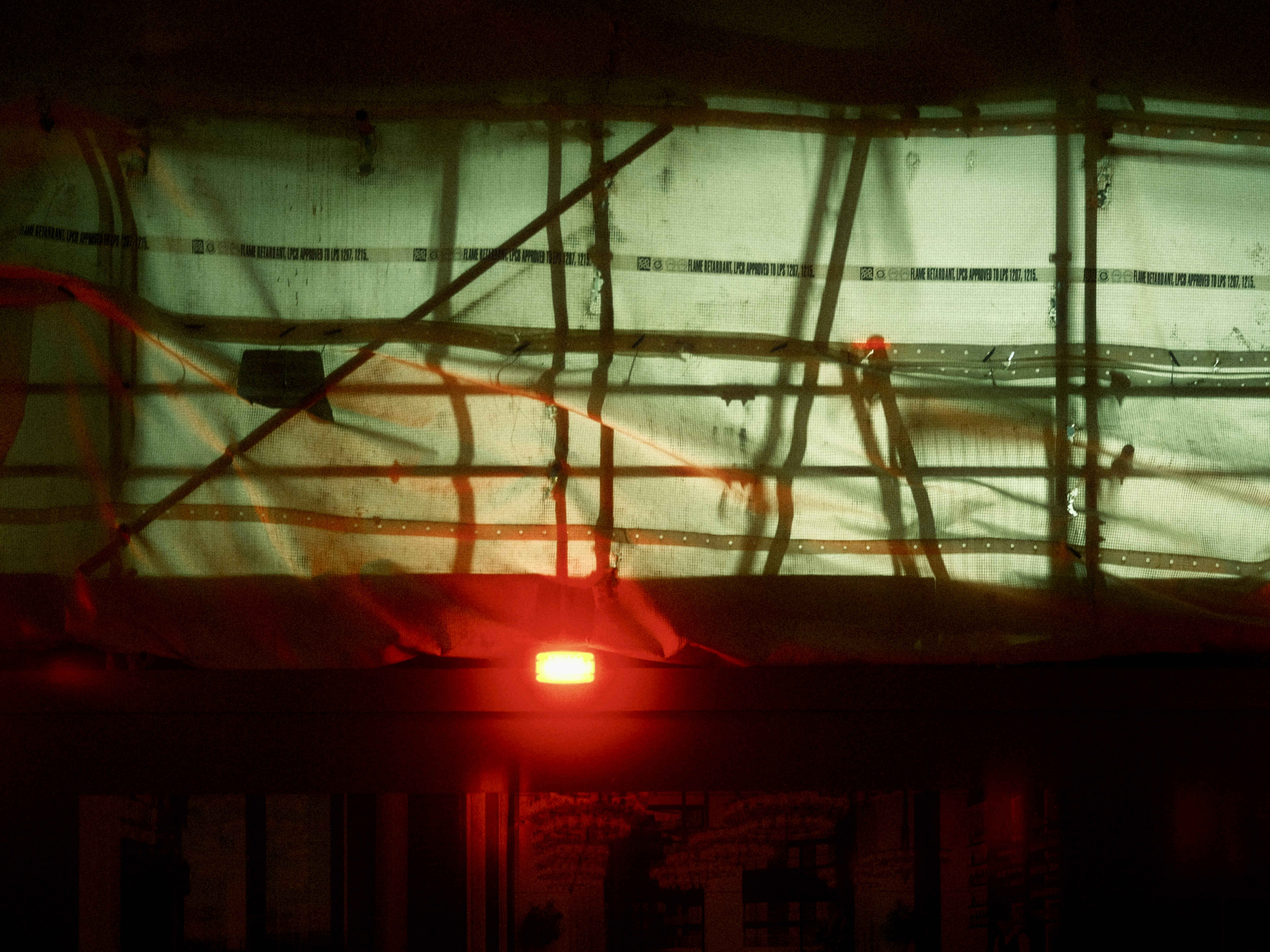 Industrial structure with green and red lighting creating dramatic shadows.