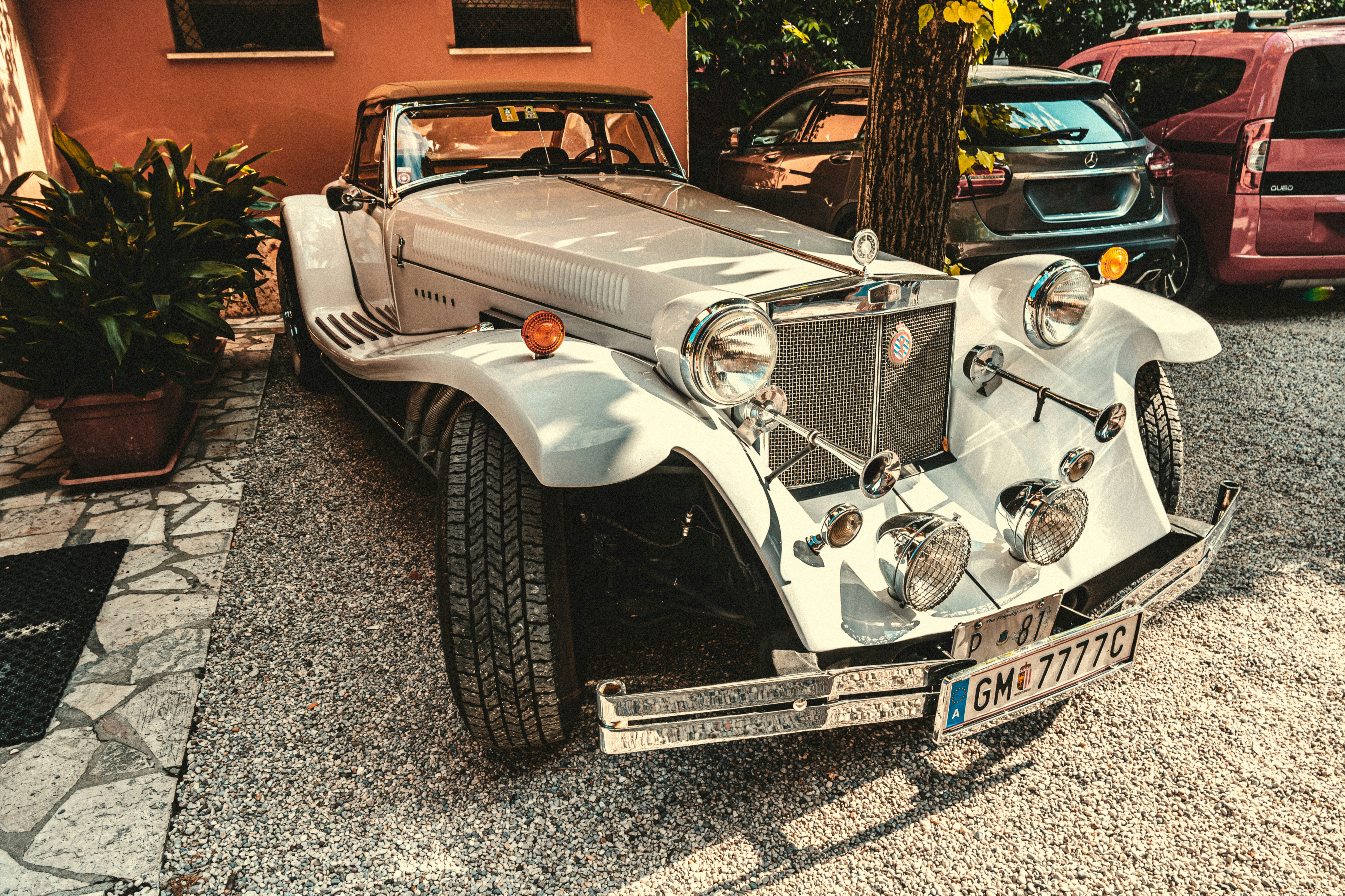 Chrome on Gravel: A Vintage Convertible at Rest in a Sunlit Driveway