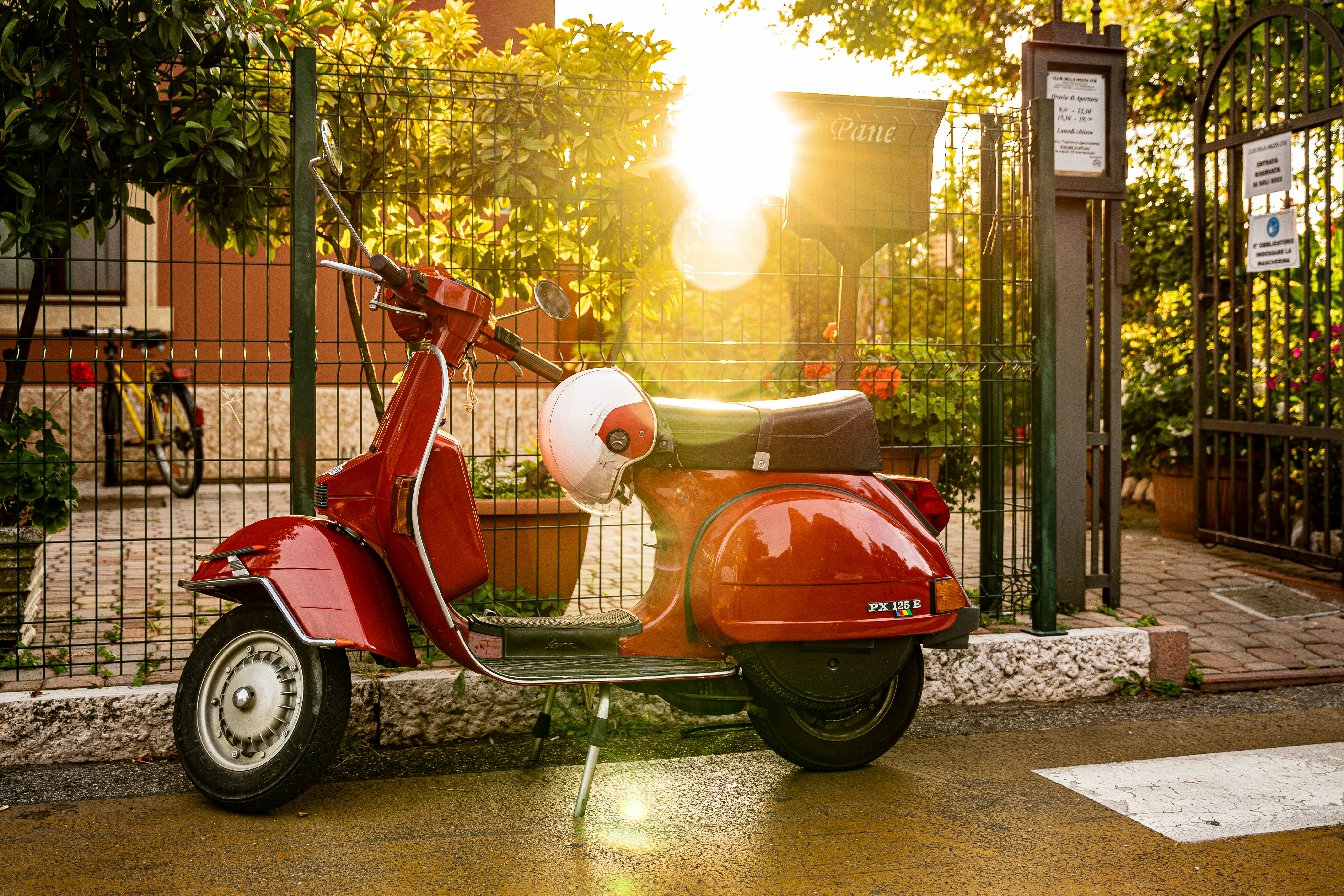 A red scooter parked in front of a gate photo – Free Italy Image on ...