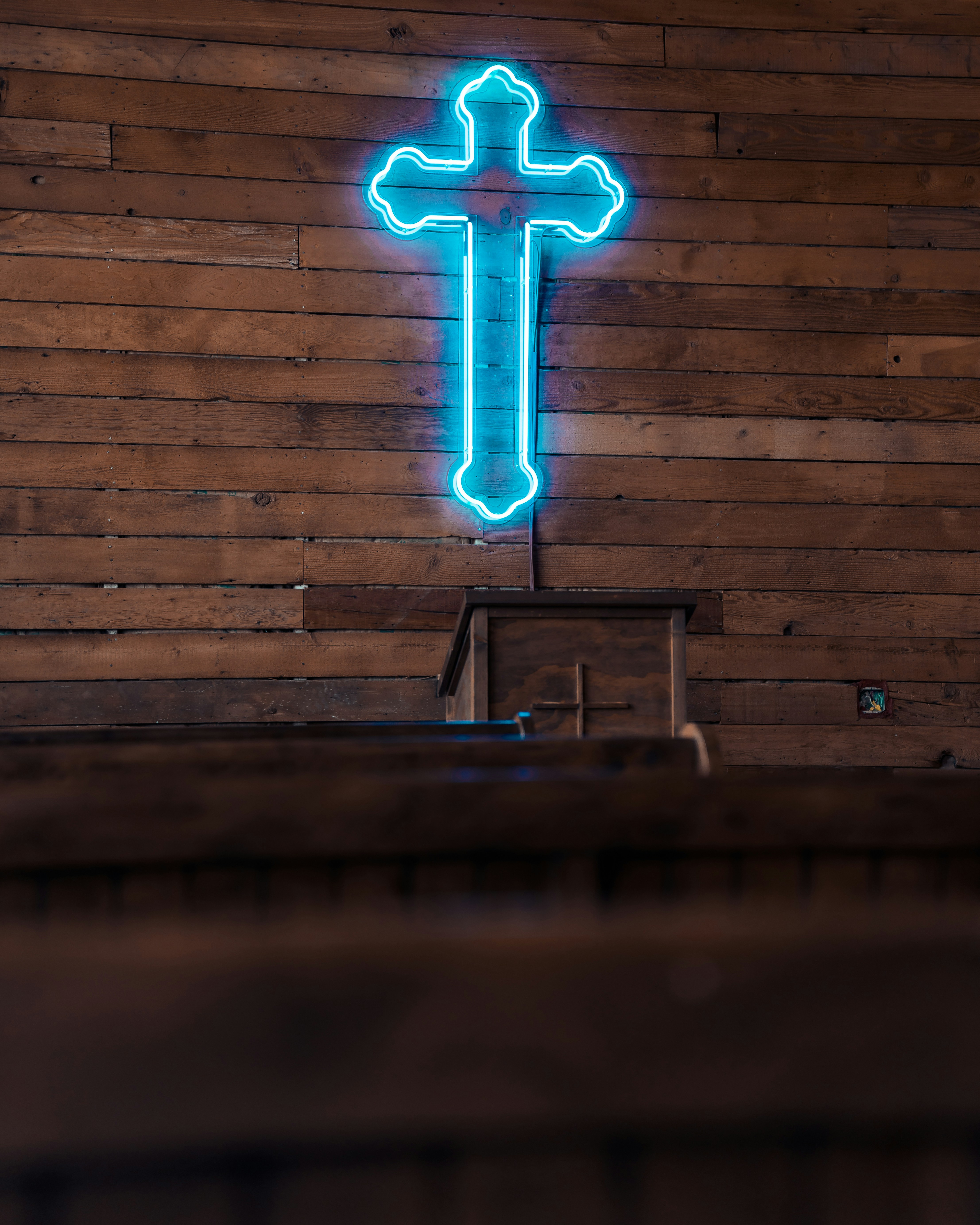 A neon blue cross on a wooden wall photo – Free Light Image on Unsplash