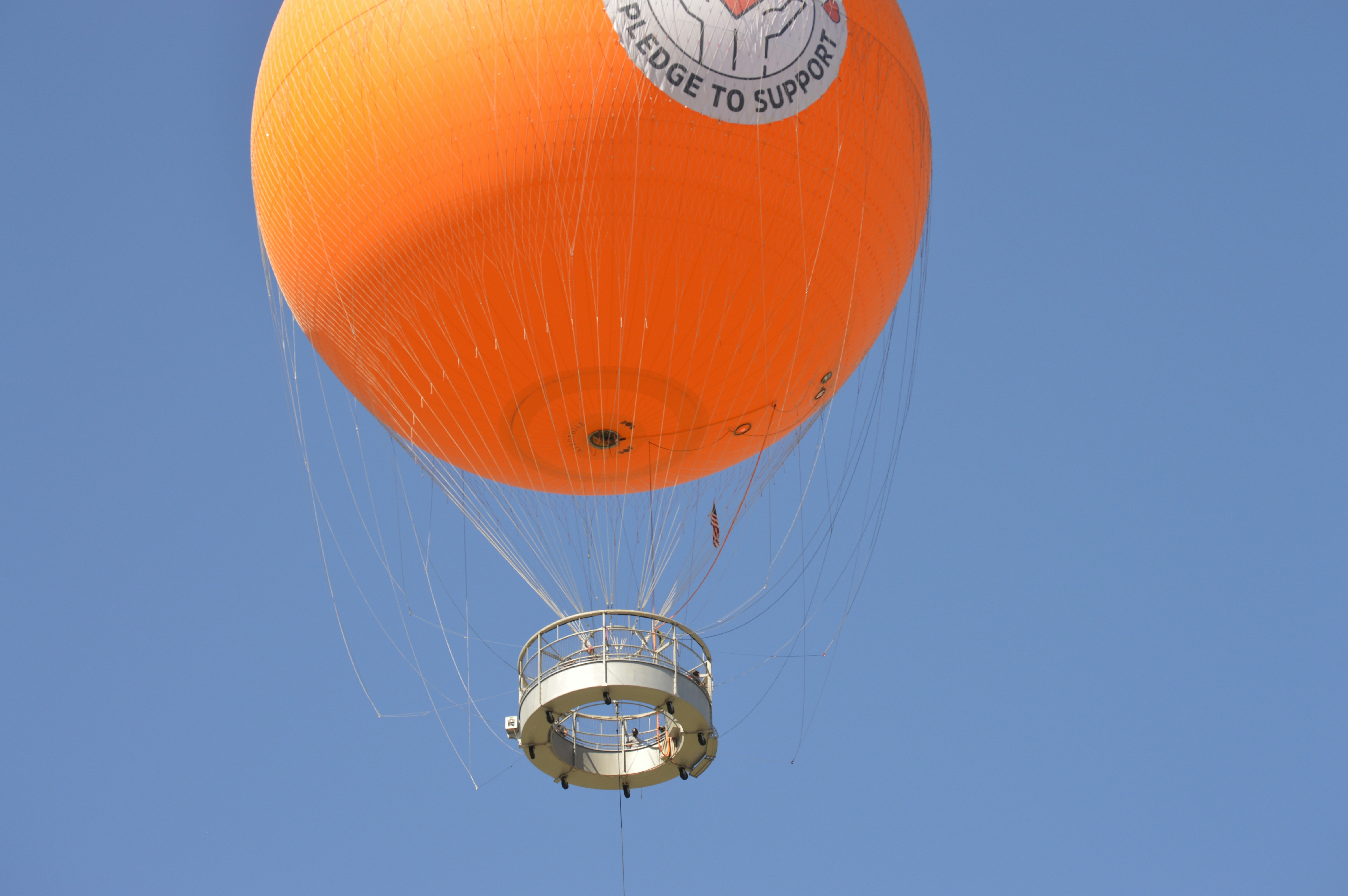 Orange Balloon Gondola Drifts Against a Pristine Blue Sky