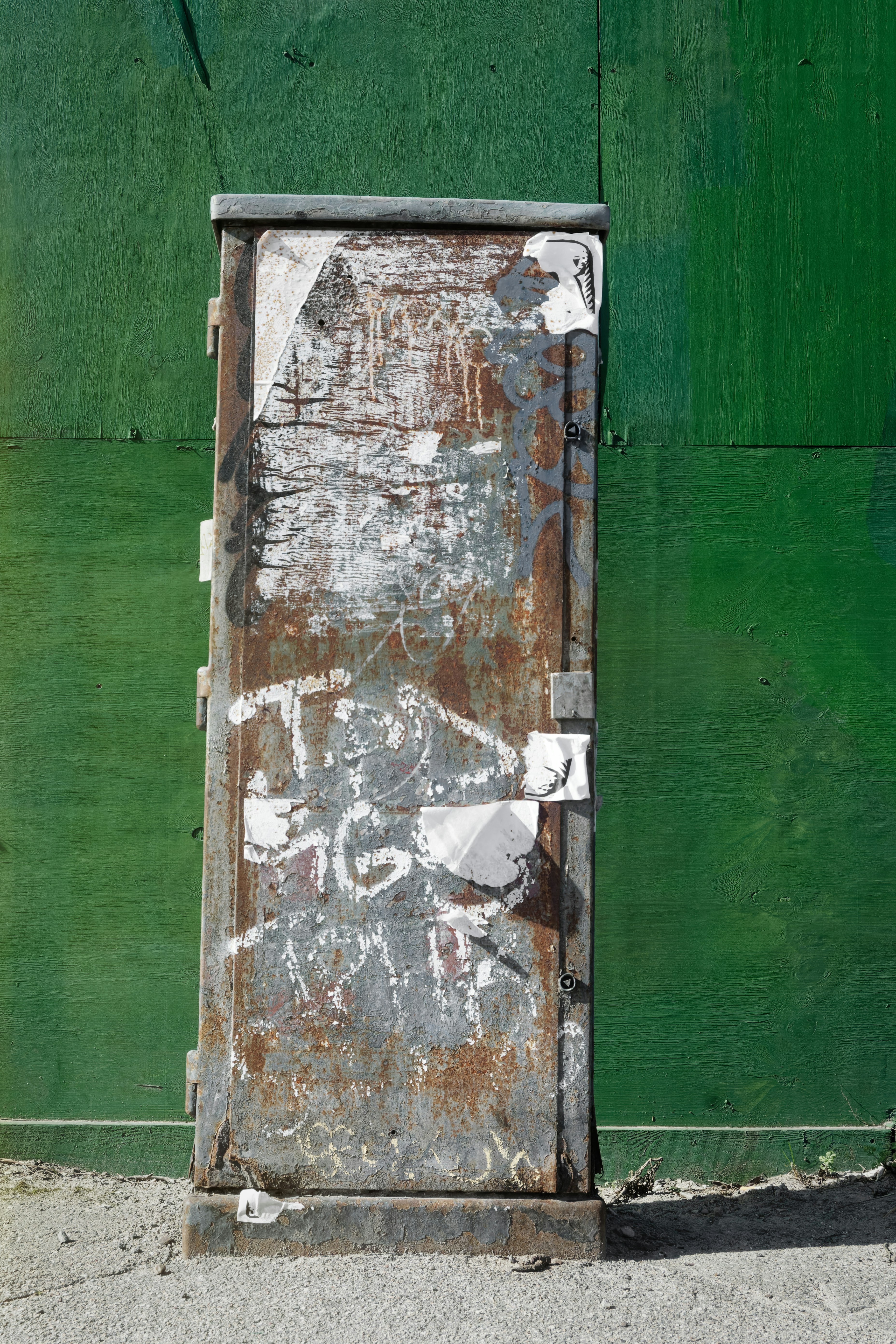 Emerald Facade, Rusted Sentinel: Graffiti Weather on a Quiet Urban Door