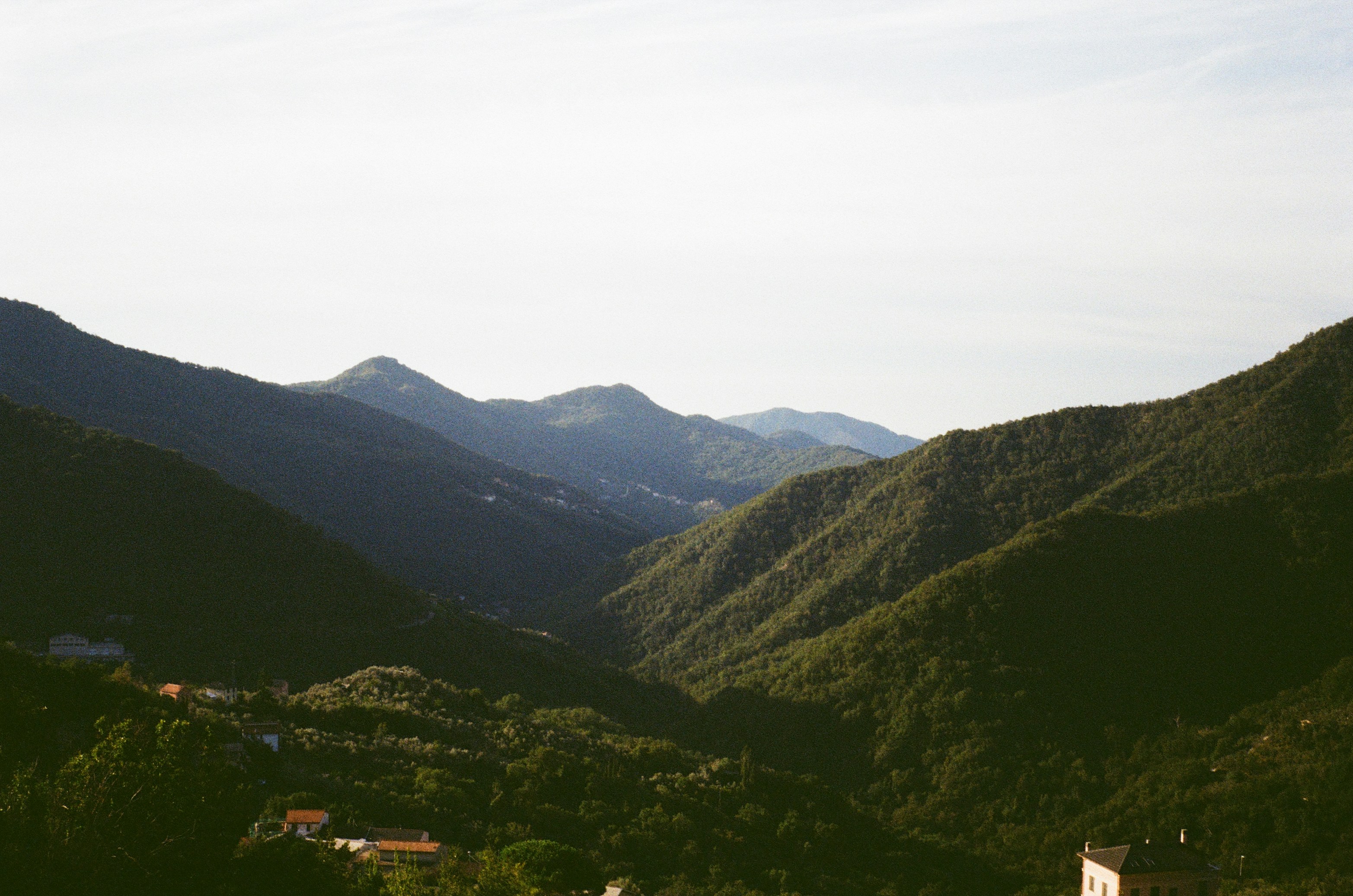 Vast green mountains stretch under a soft sky, creating a serene landscape that invites exploration.