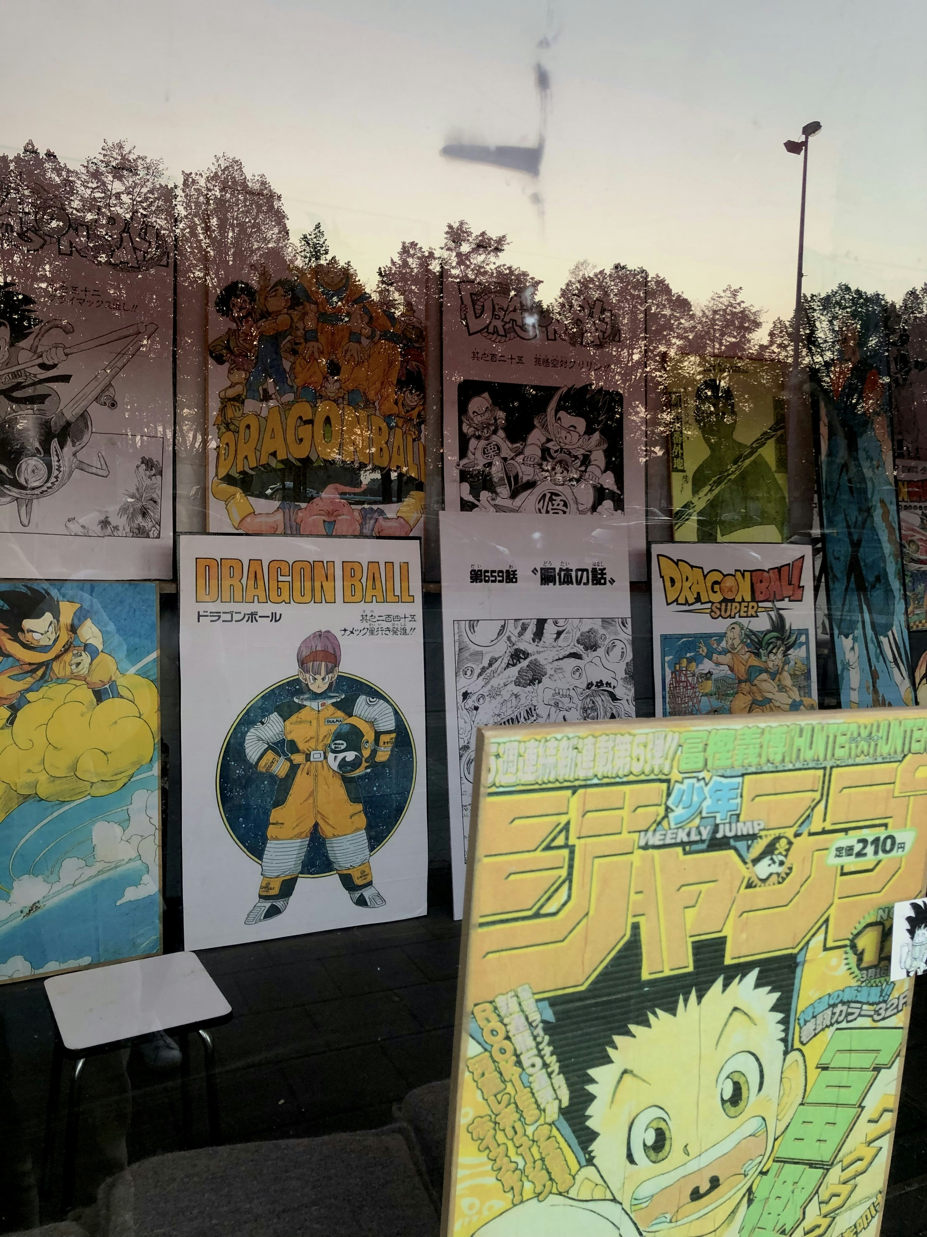 Dragon Ball Window Gallery: A Wall of Manga Posters, Reflections, and Bold Foreground Art