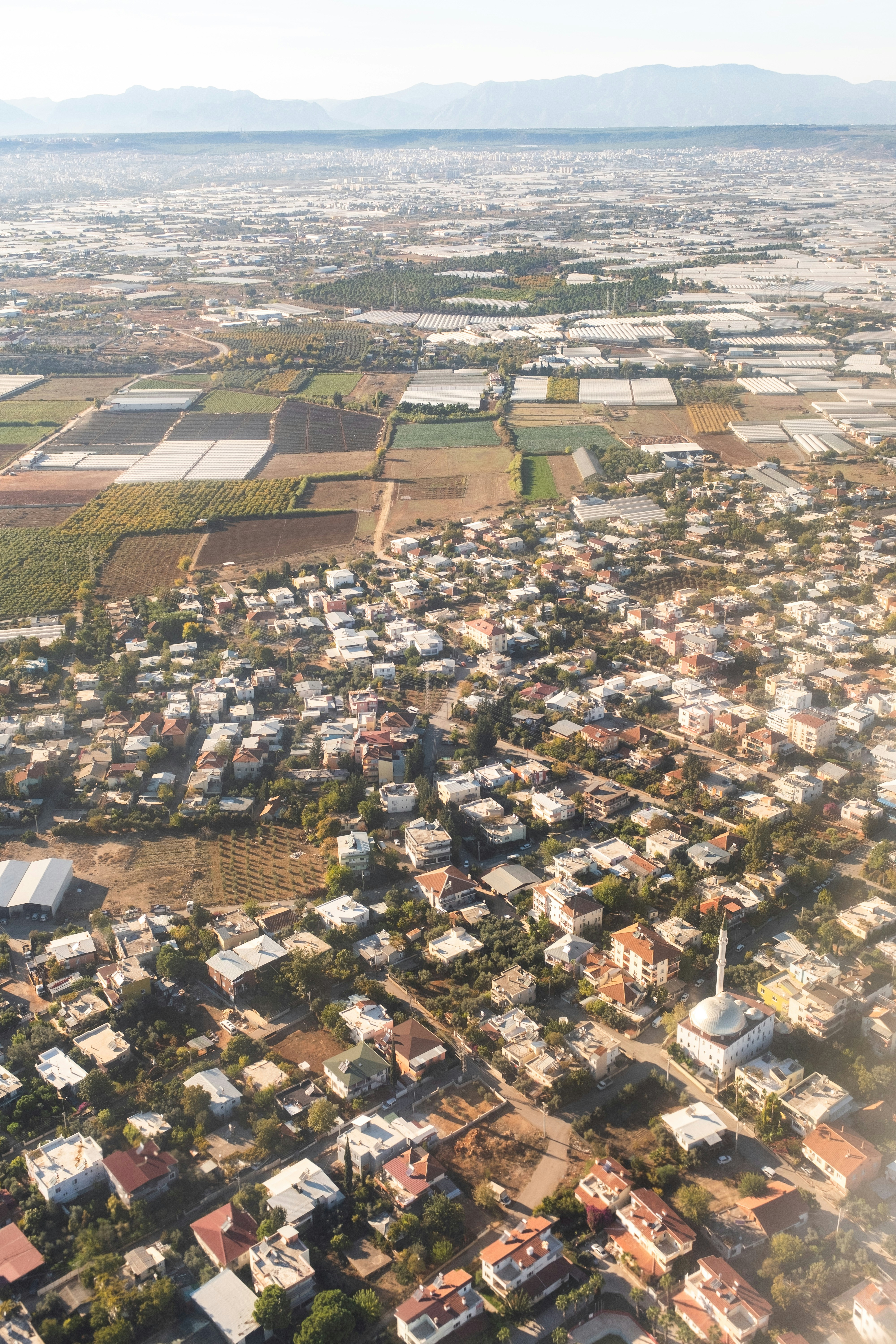 Aerial mosaic: countryside farms and clustered town beneath a hazy horizon