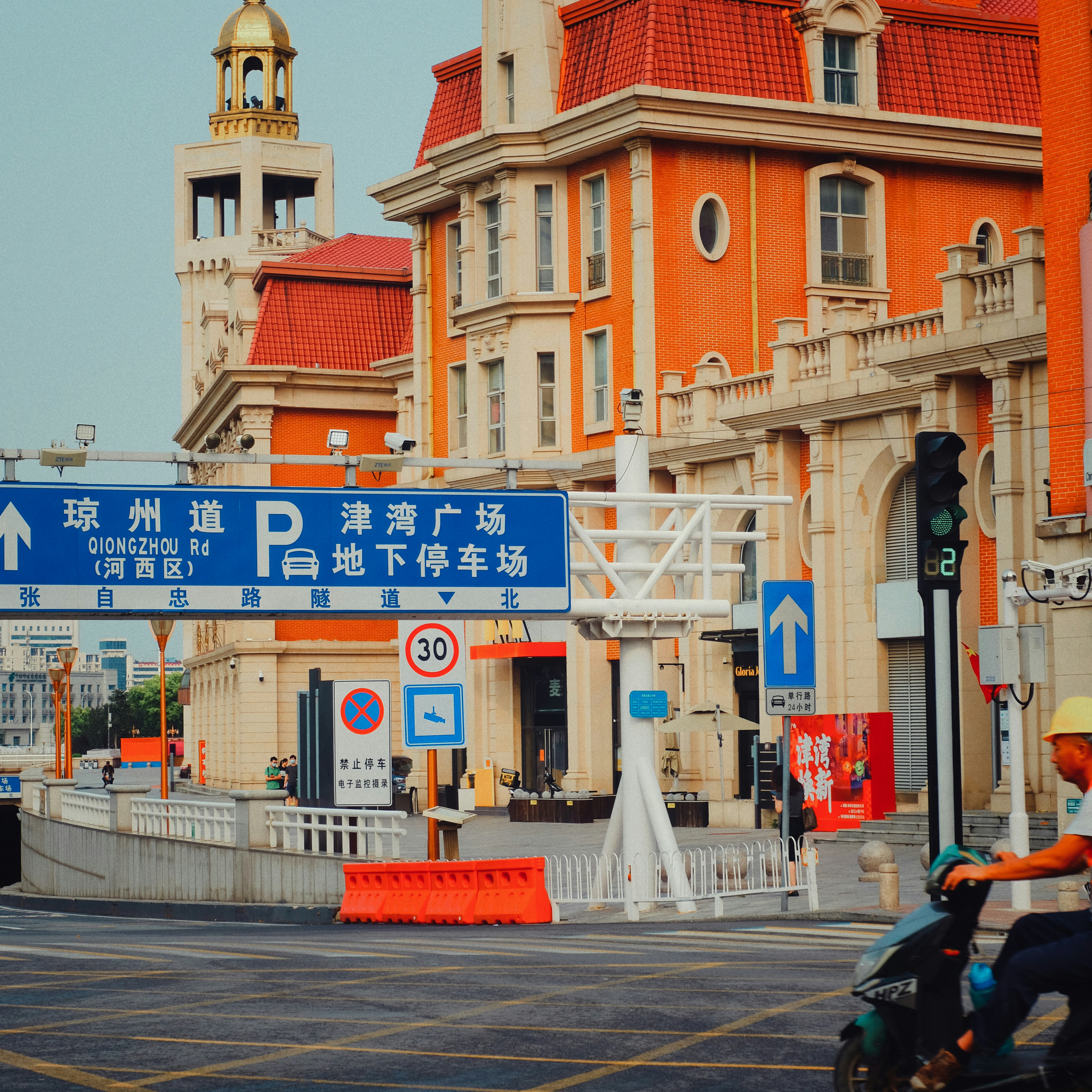 Vibrant street scene with red-roofed buildings and traffic signs under a clear sky.