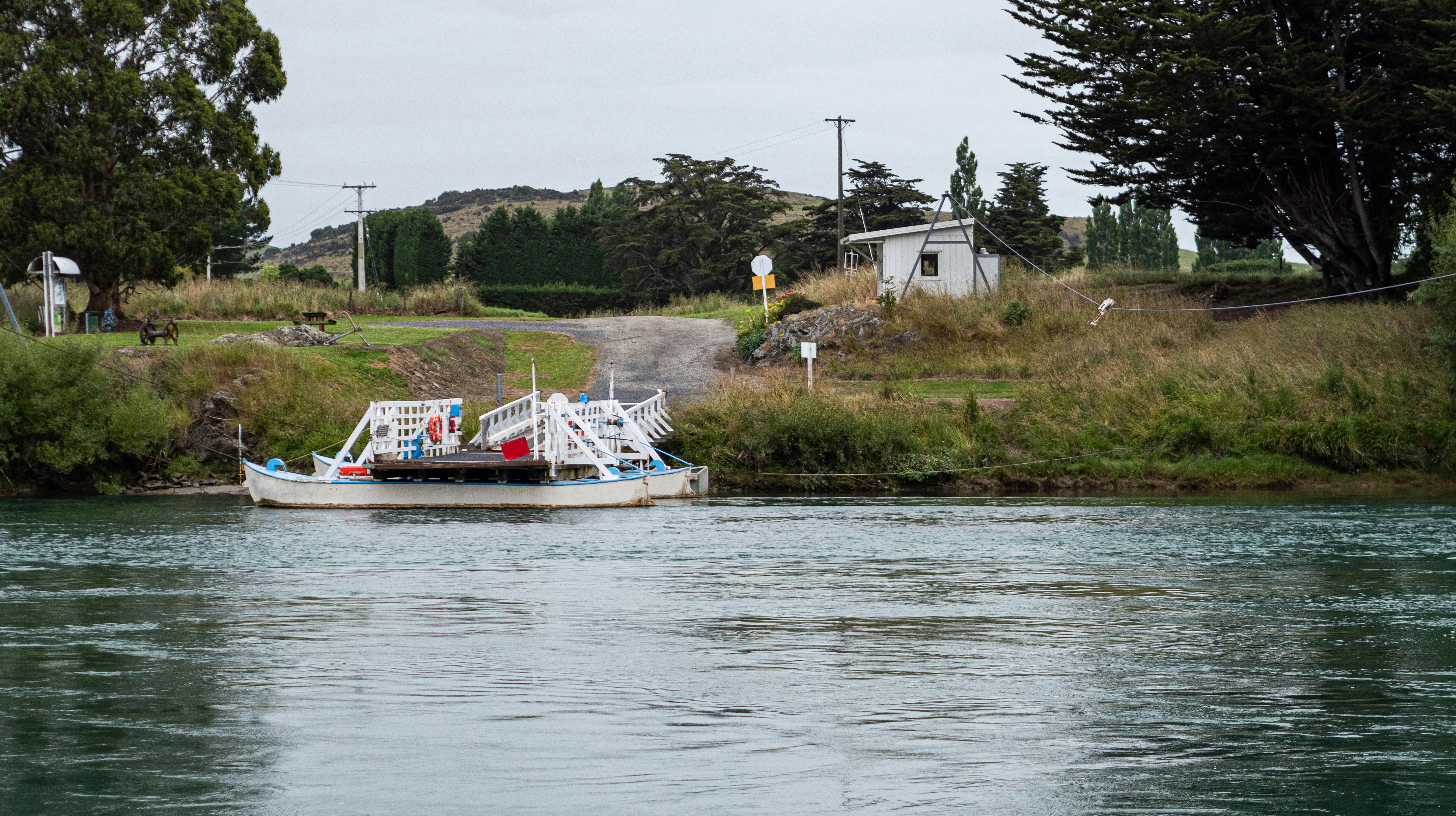 Riverbound: A Small Workboat Resting Along a Lush Riverside