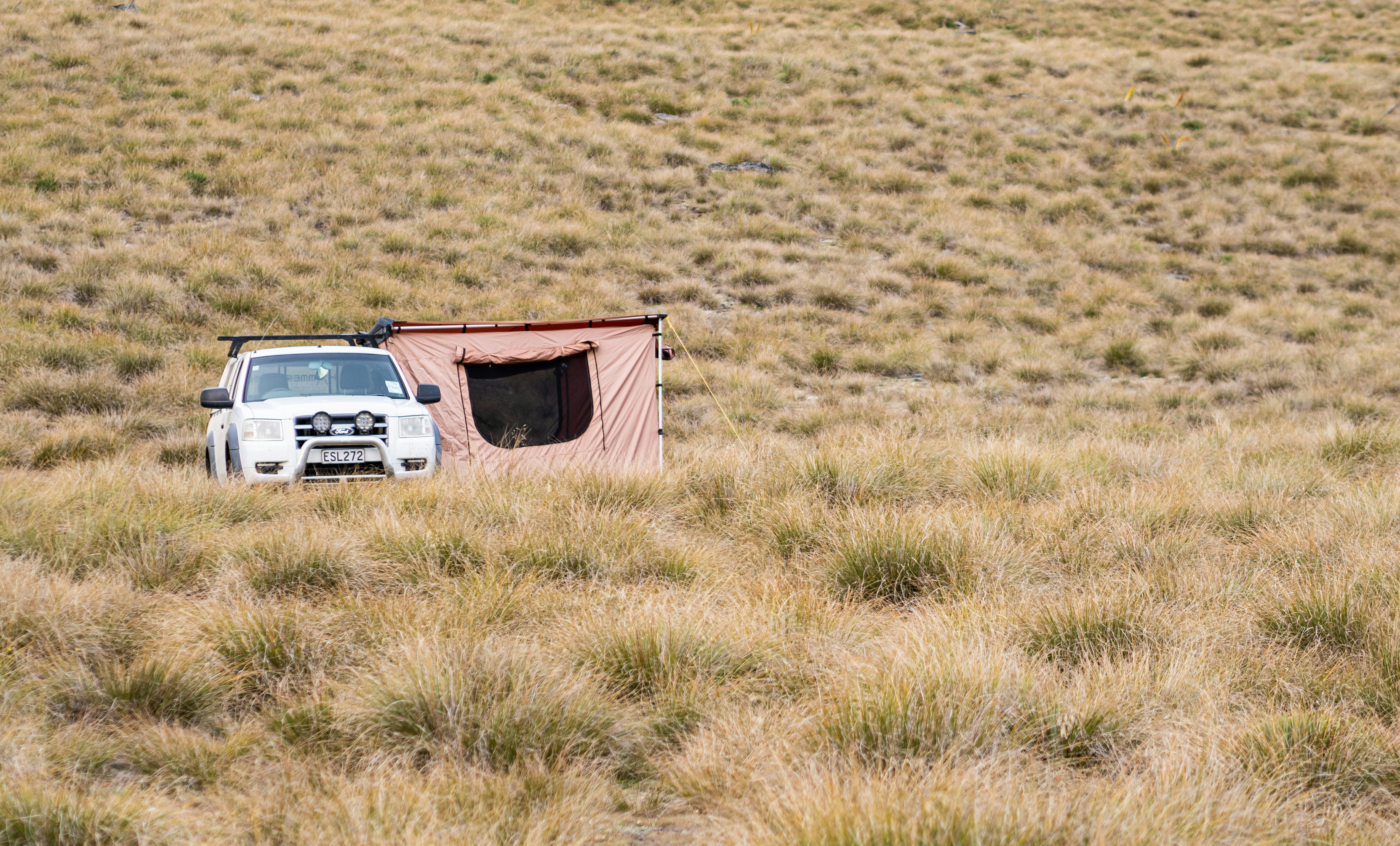 a truck parked in a field with a tent in the back