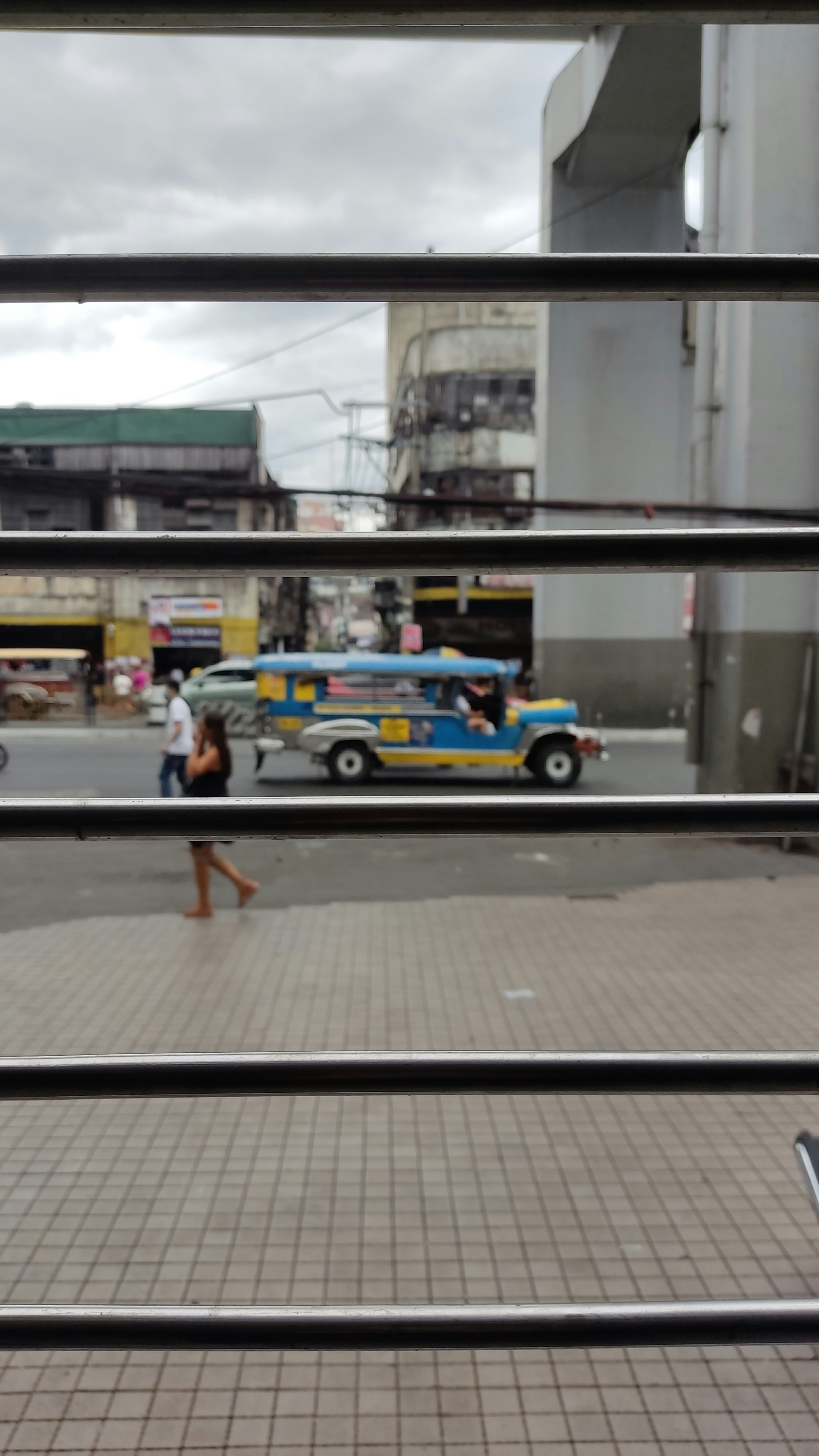 A woman walking down a street next to a tall building photo – Free Road ...
