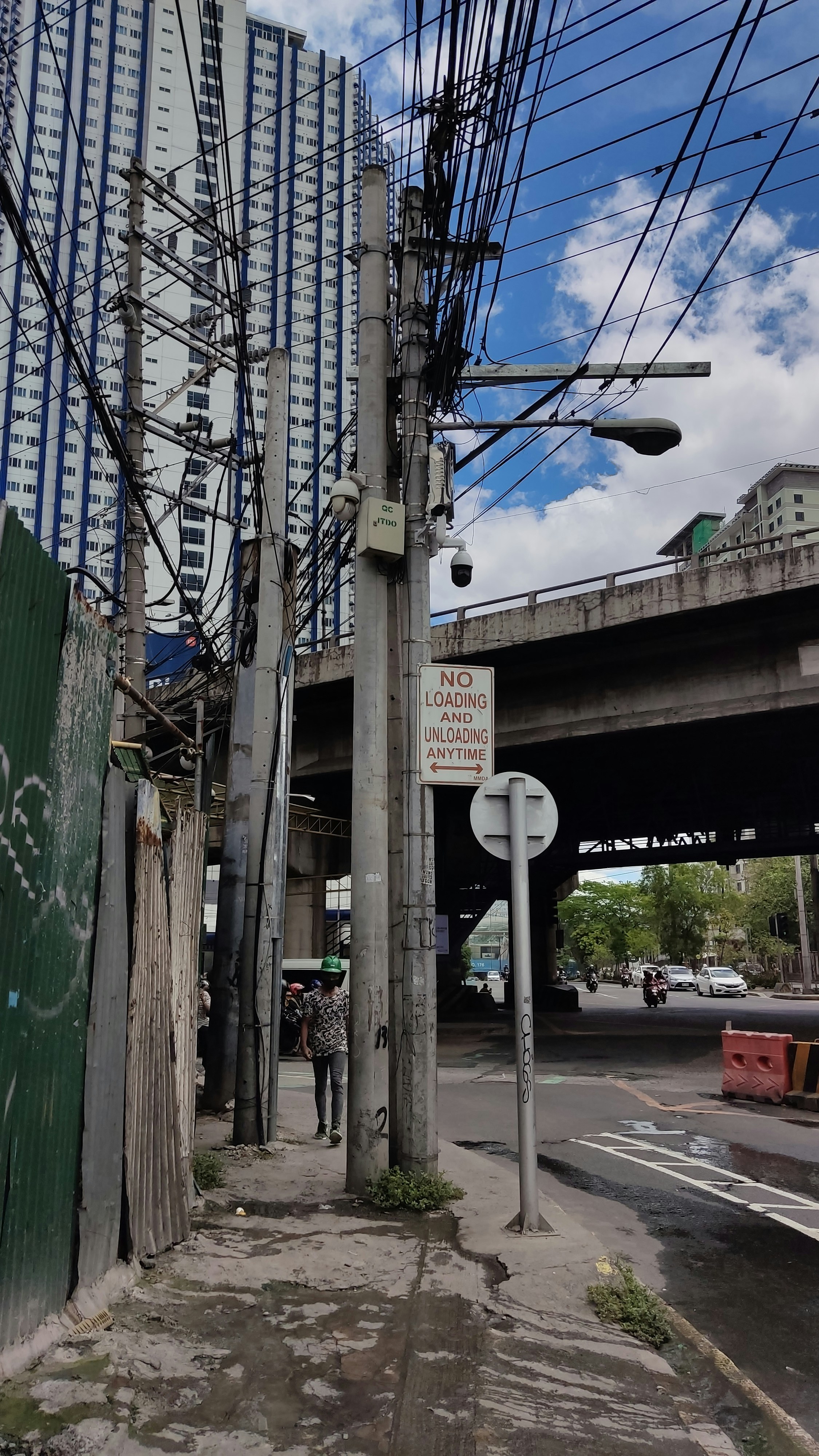 A man walking down a street next to a tall building photo – Free Road ...