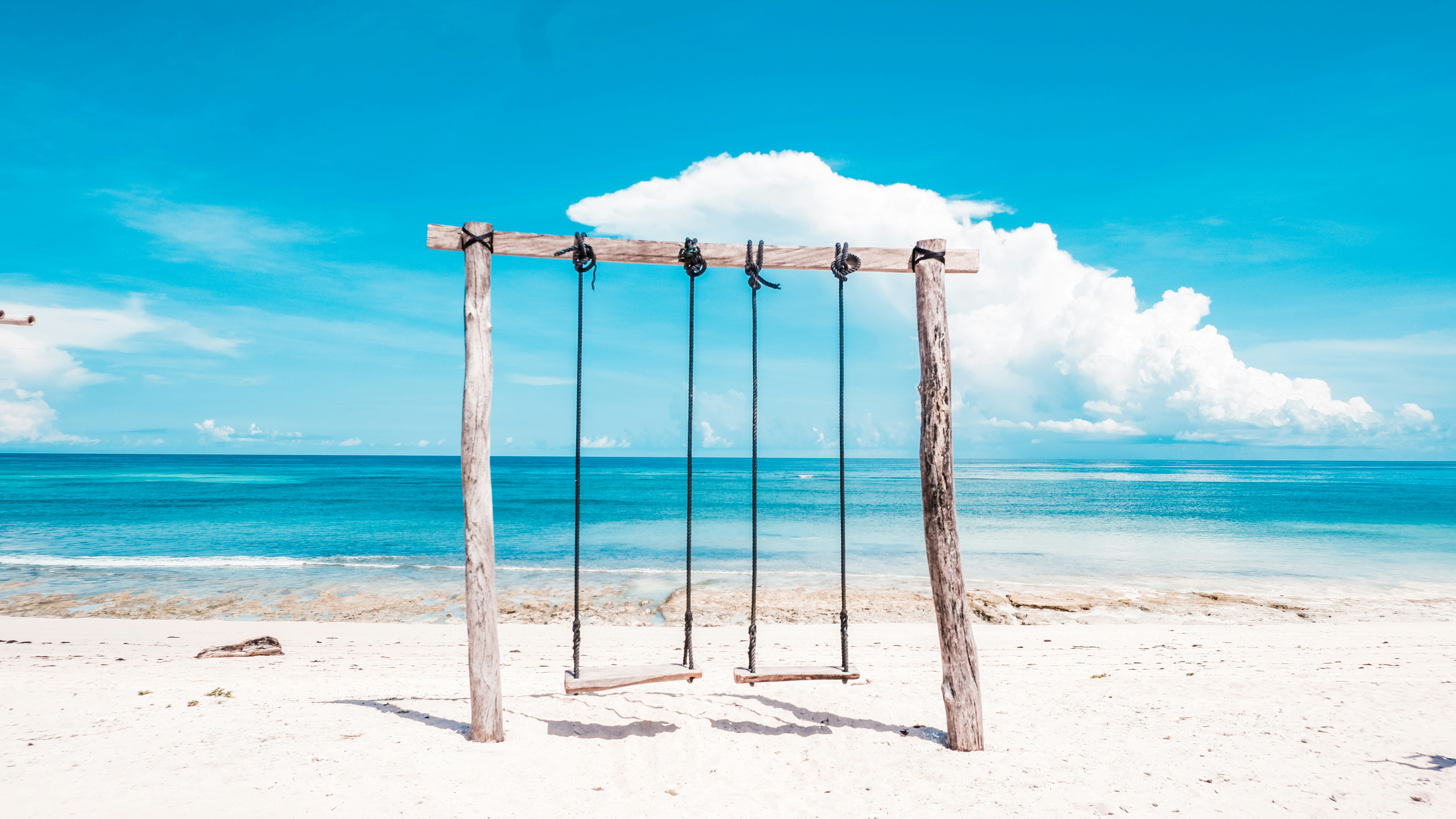 A swing set on a beach with the ocean in the background photo – Free ...