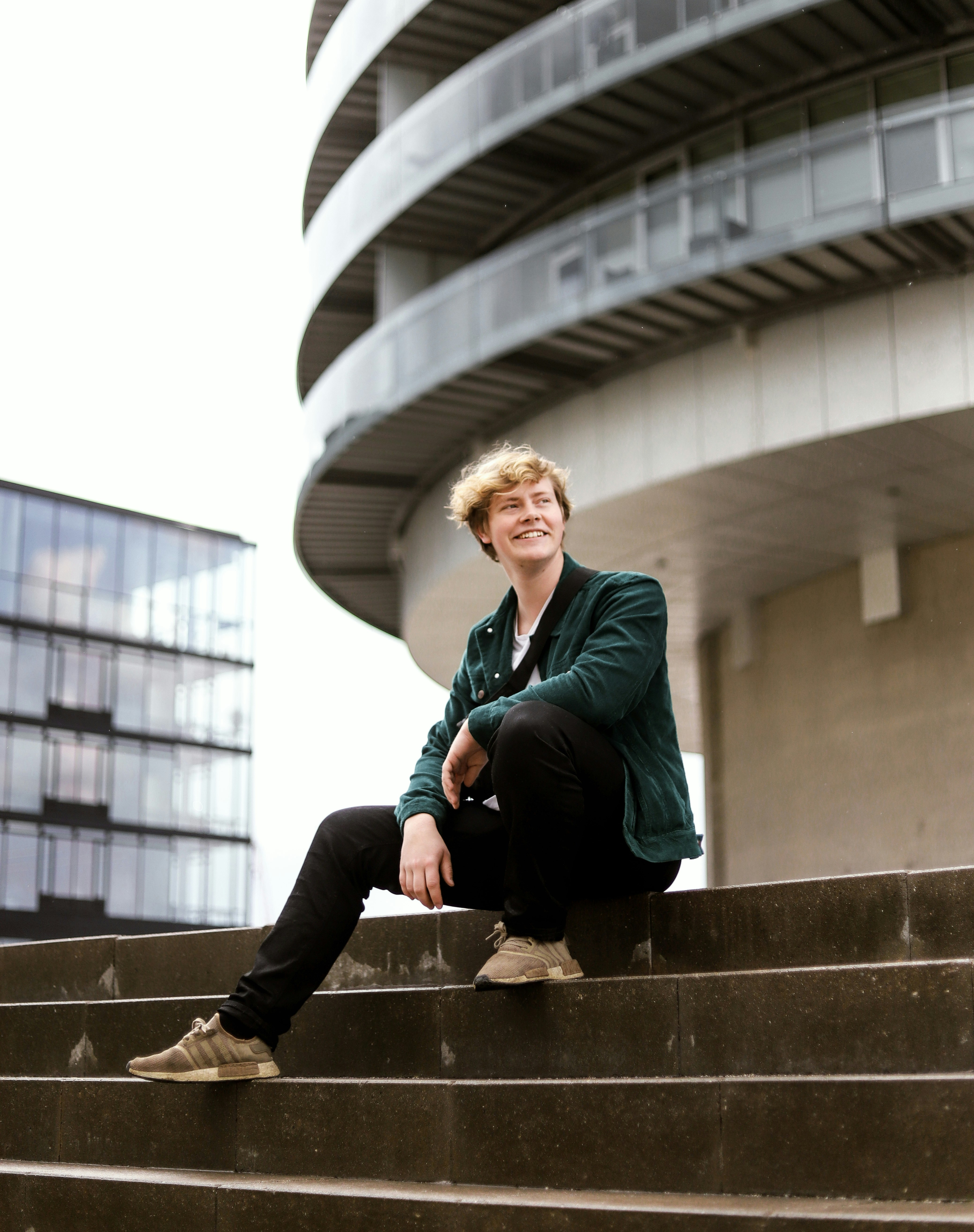 Sunlit Grin on an Urban Staircase Under a Curved Modern Tower