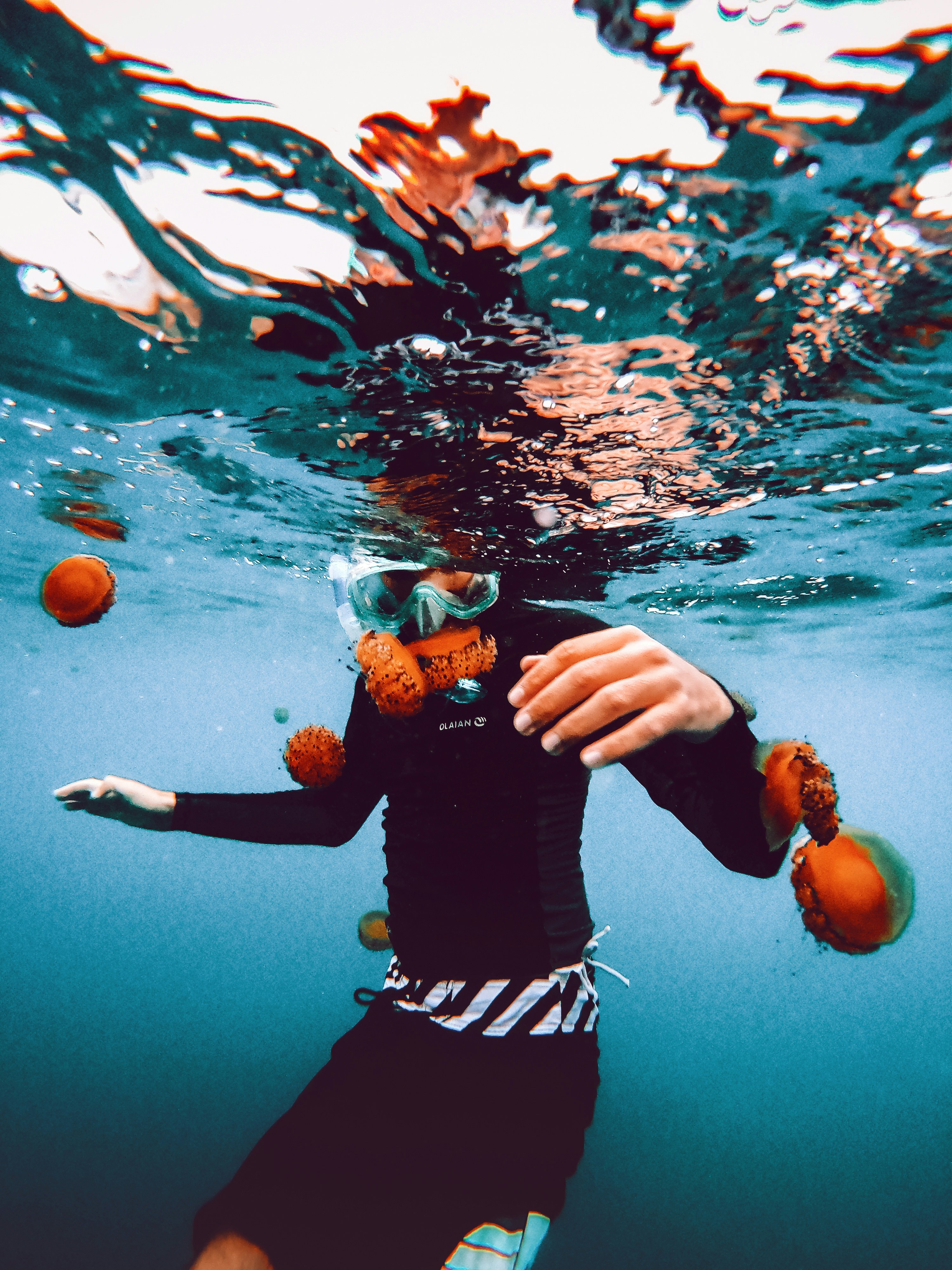 A person in a black shirt and some orange balls in the water photo ...