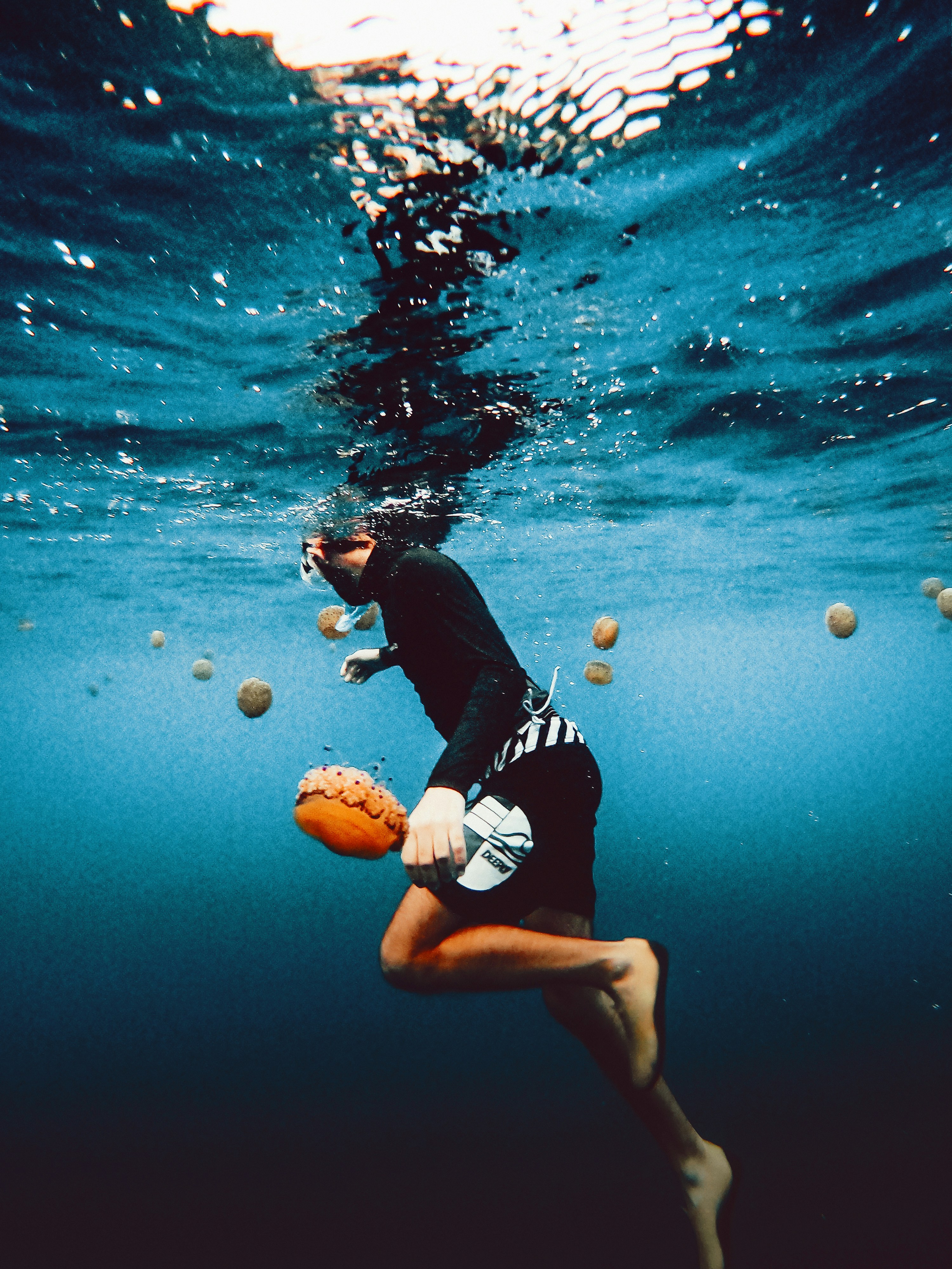 Underwater Runner: A Surfer’s Silhouette in Coral-Orange Hands