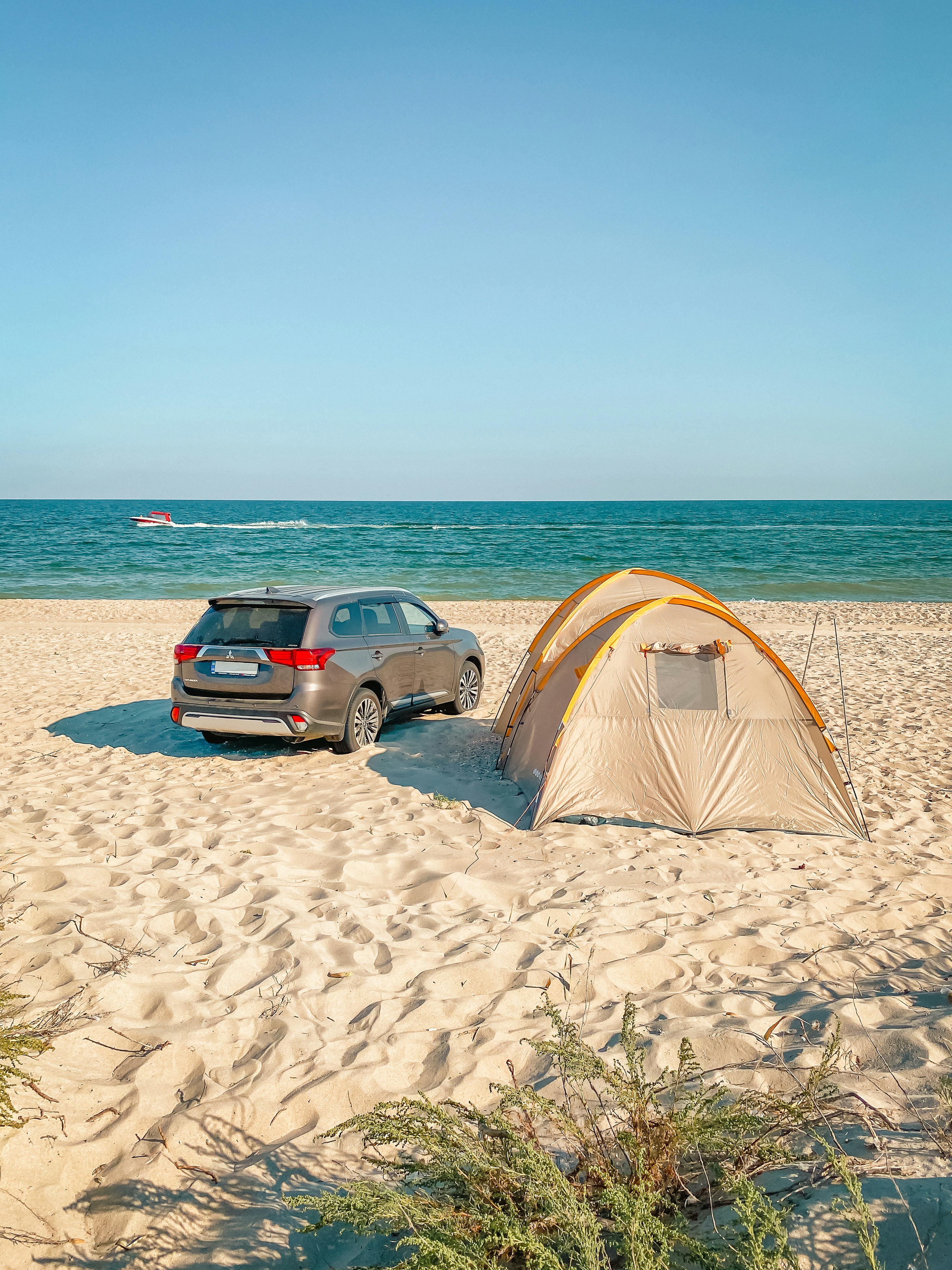 Sandbound: A Quiet Beach Camp with SUV and Orange Tent Under a Clear Sky