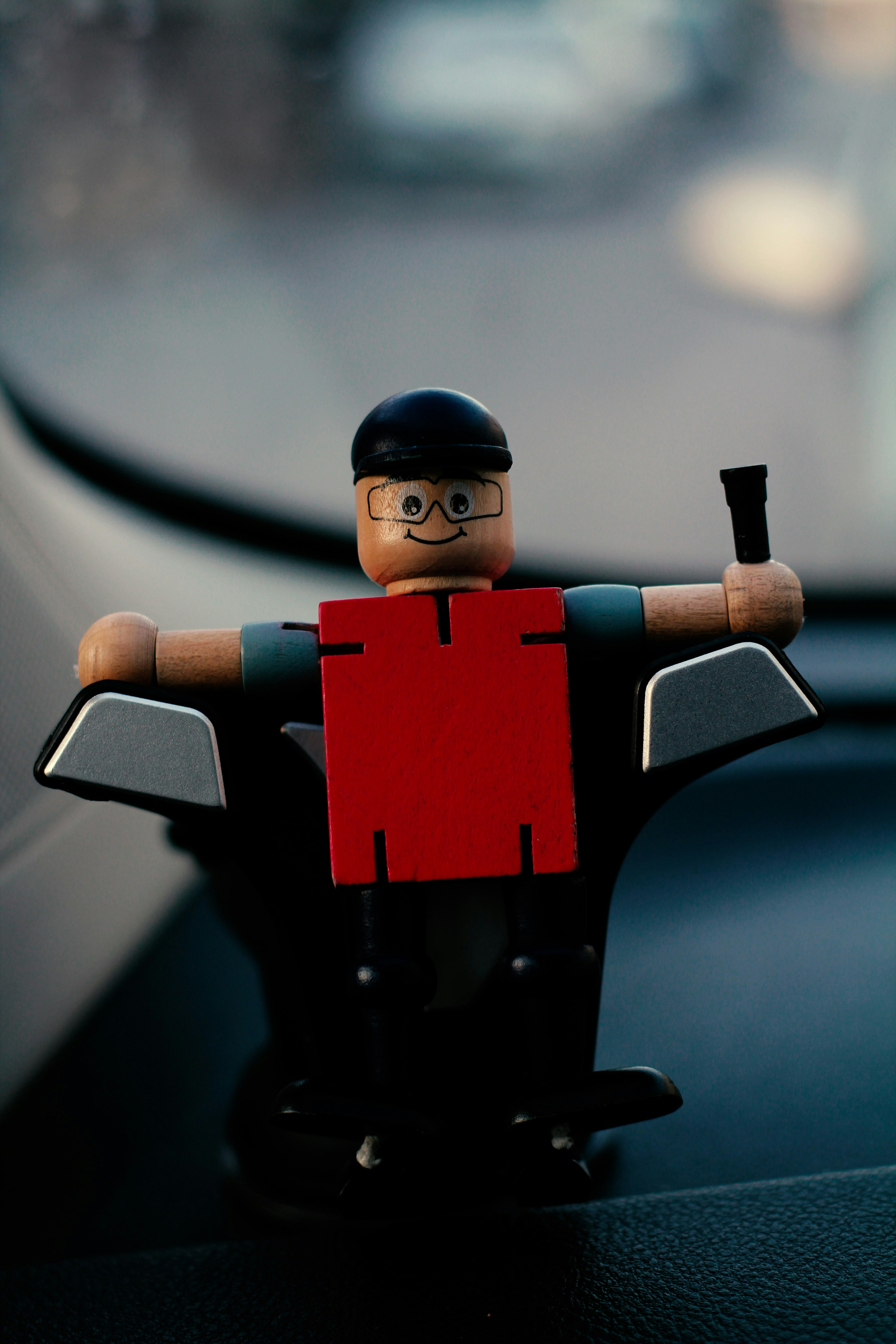 Dashboard Daredevil: A Tiny Wooden Figure Commands the Blurred Roadscape