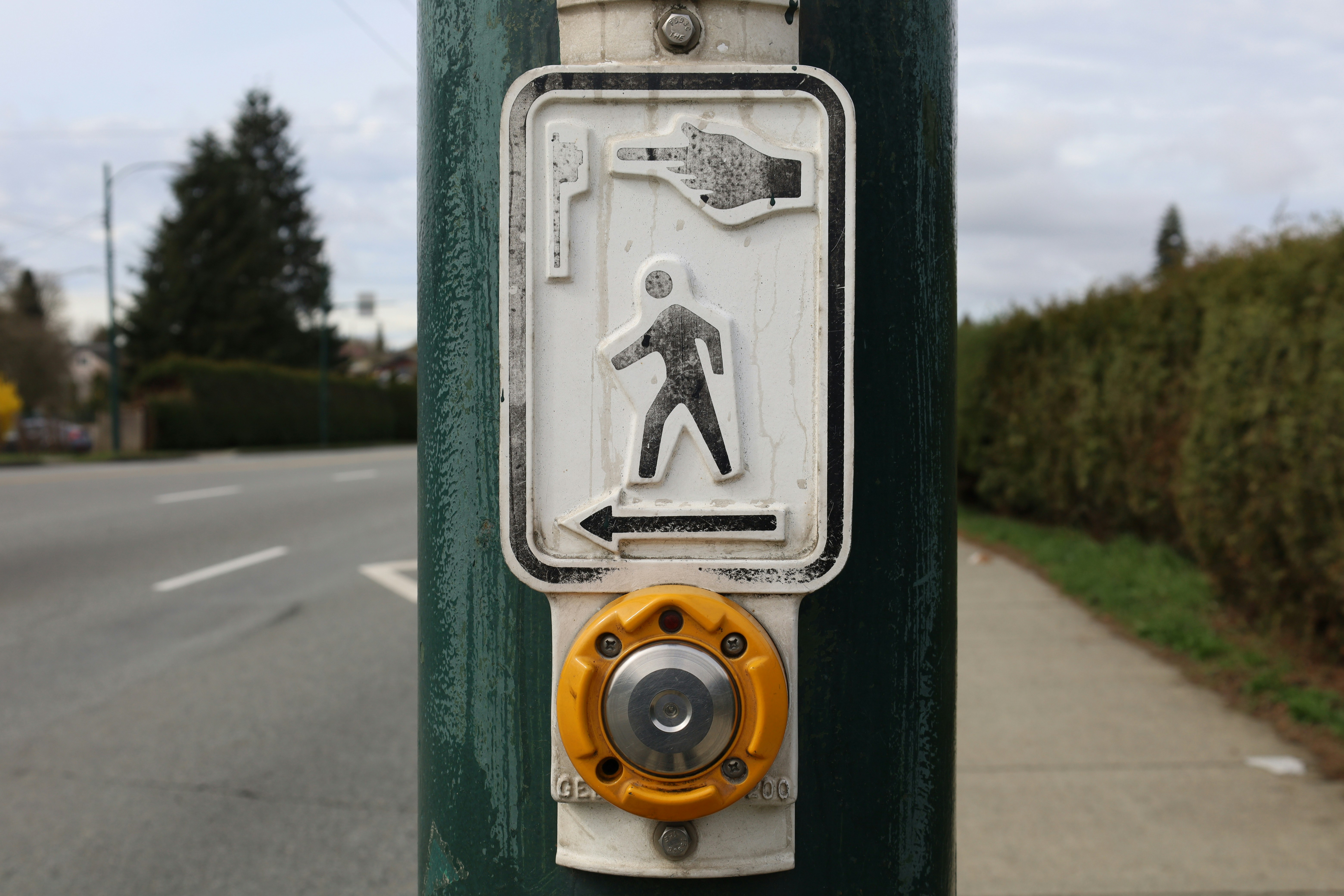 Weathered Pedestrian Button Anchored by a Walking Sign on a Quiet Street Pole