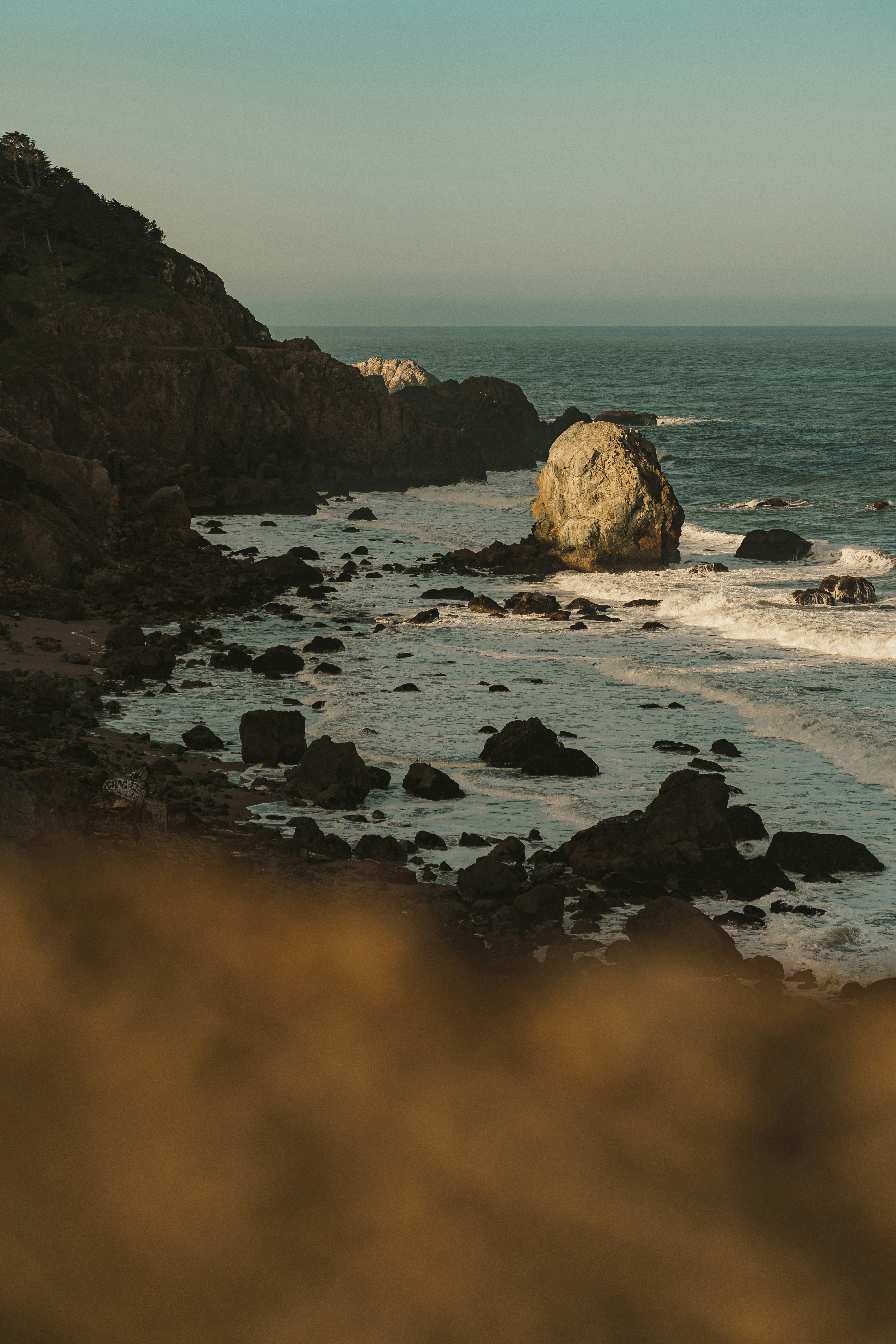 A large rock sticking out of the ocean next to a beach photo – Free ...