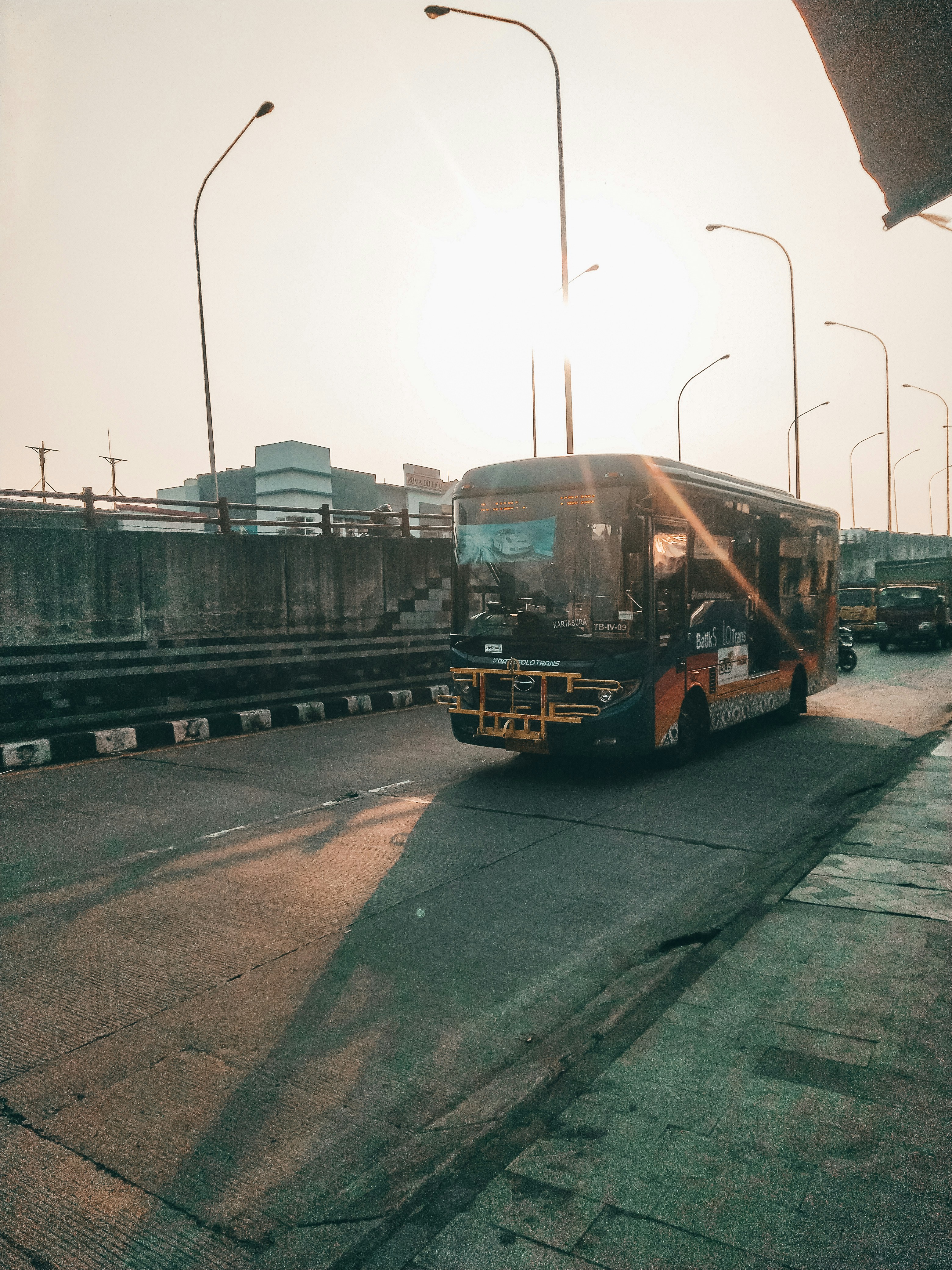 A bus driving down a street next to a bridge photo – Free Palur kulon ...