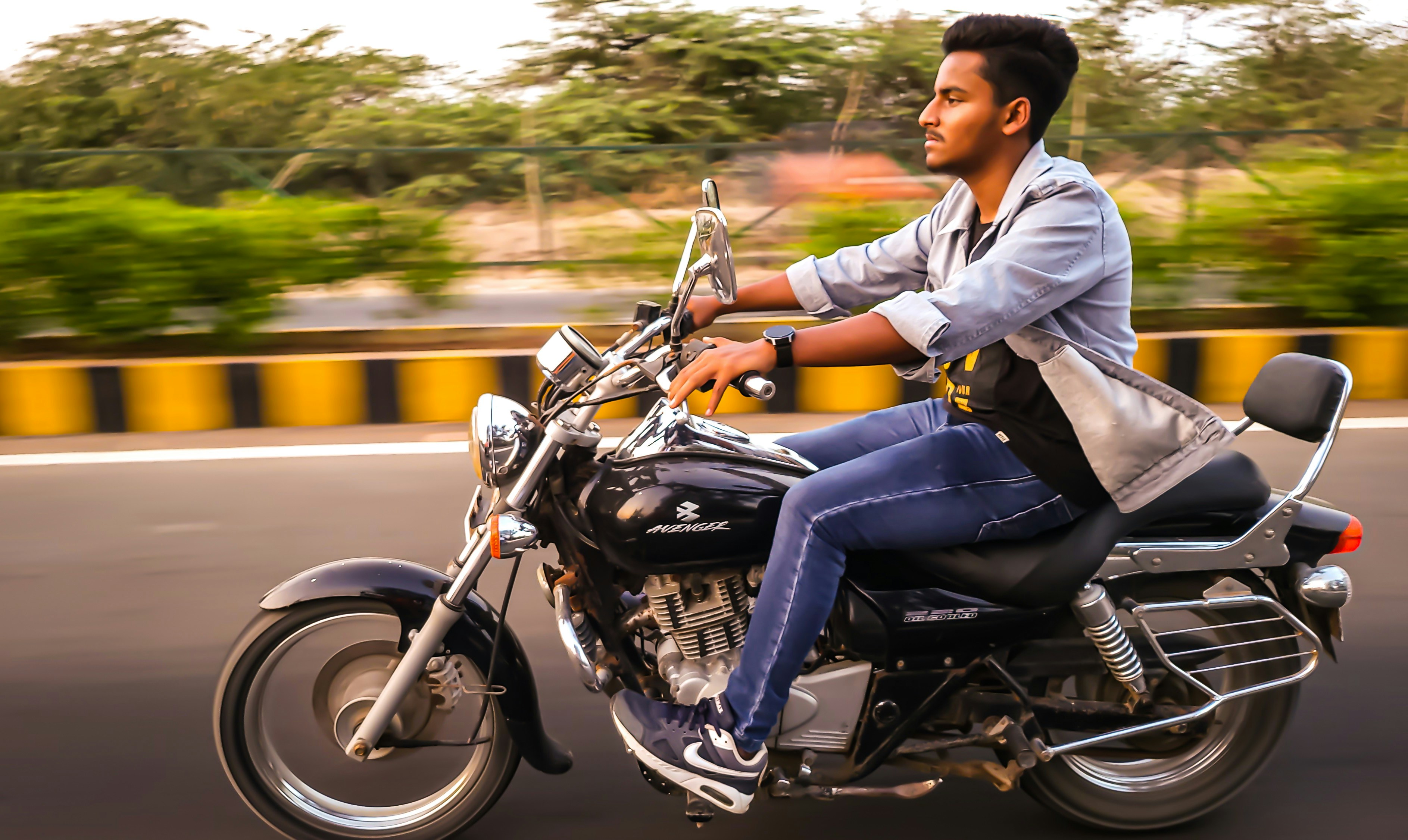 A man riding on the back of a motorcycle down a street photo – Free Diu ...