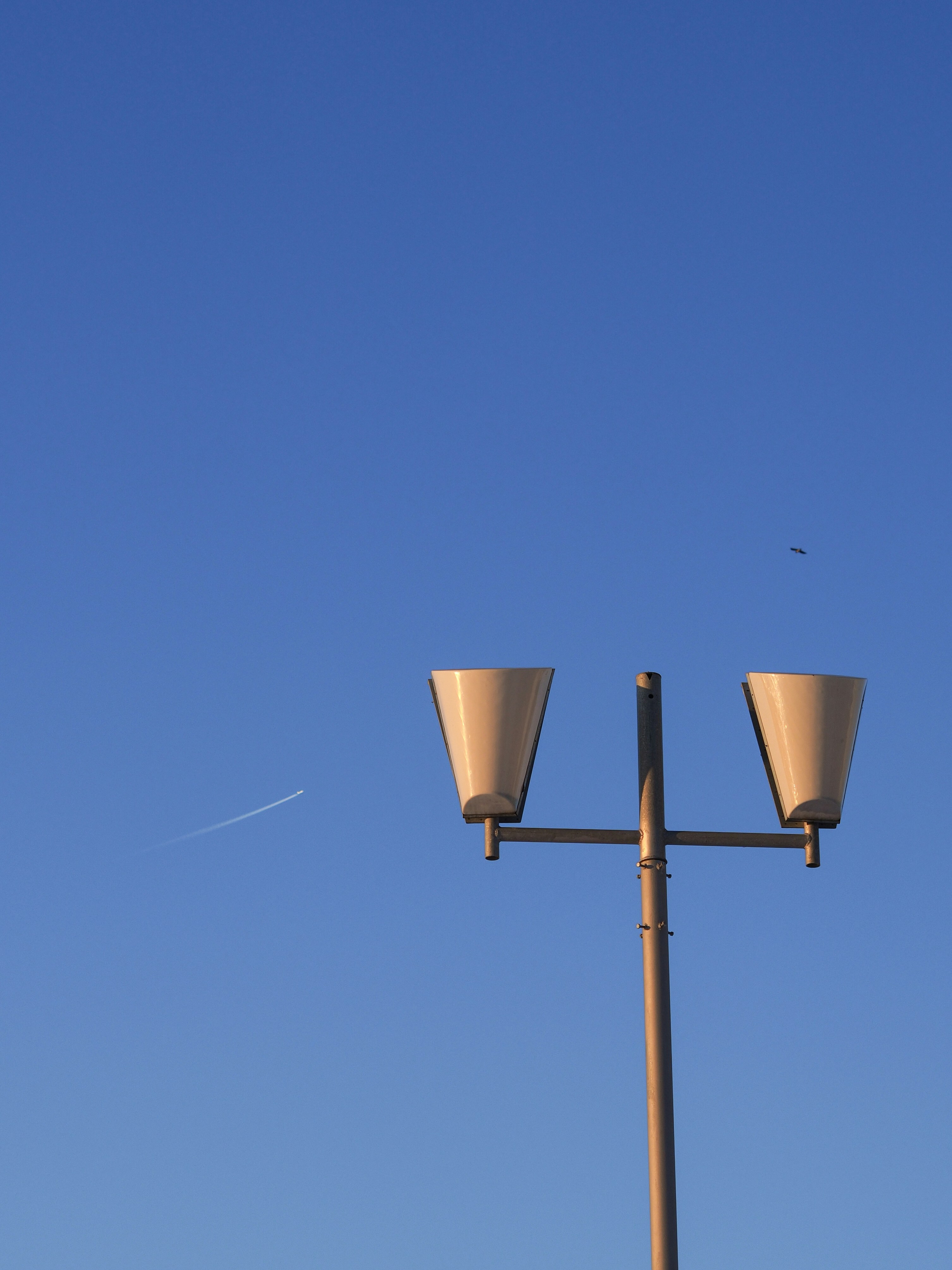 a street light with a plane flying in the background