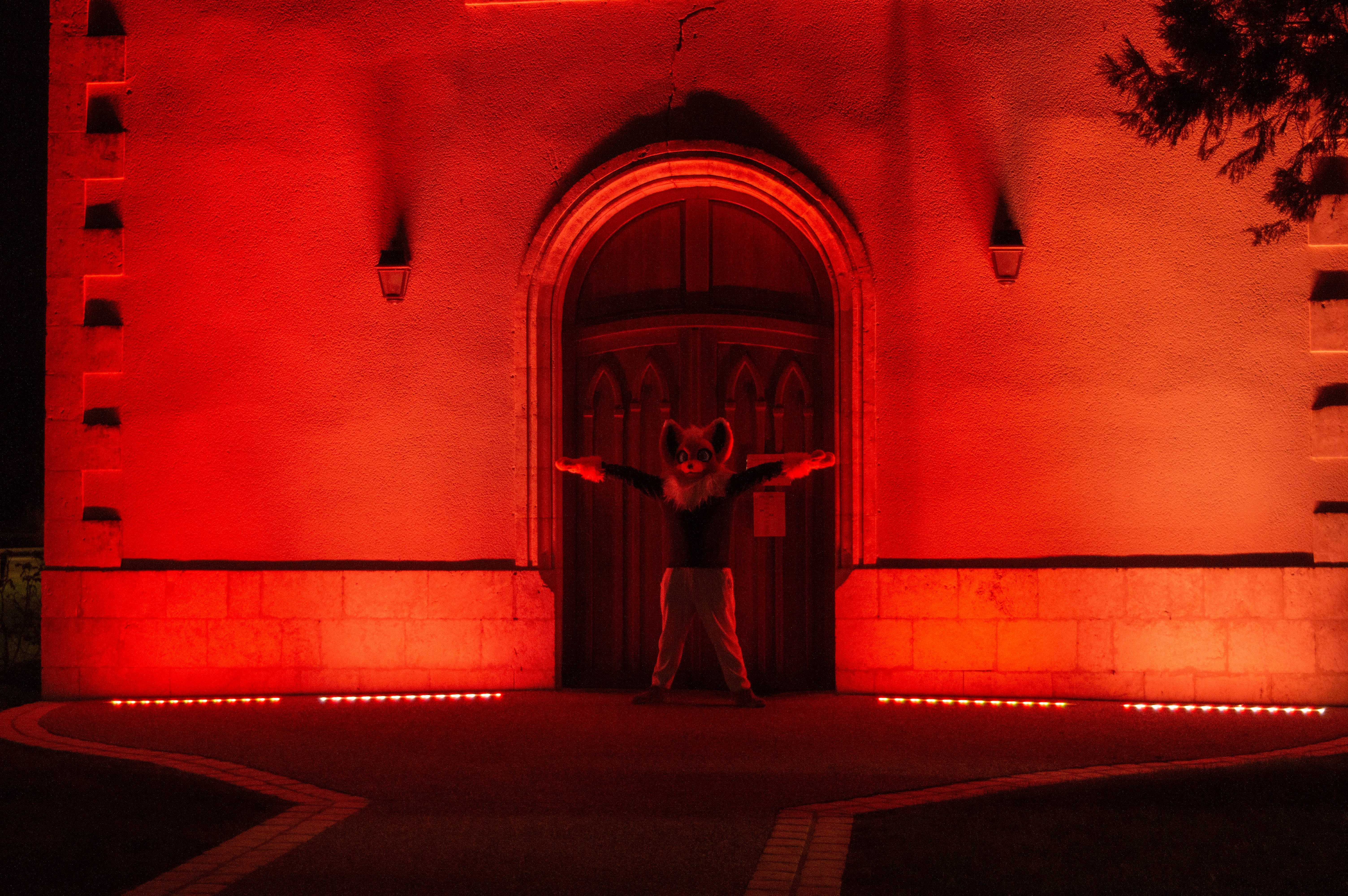 A man standing in front of a red lit building photo – Free Lighting ...
