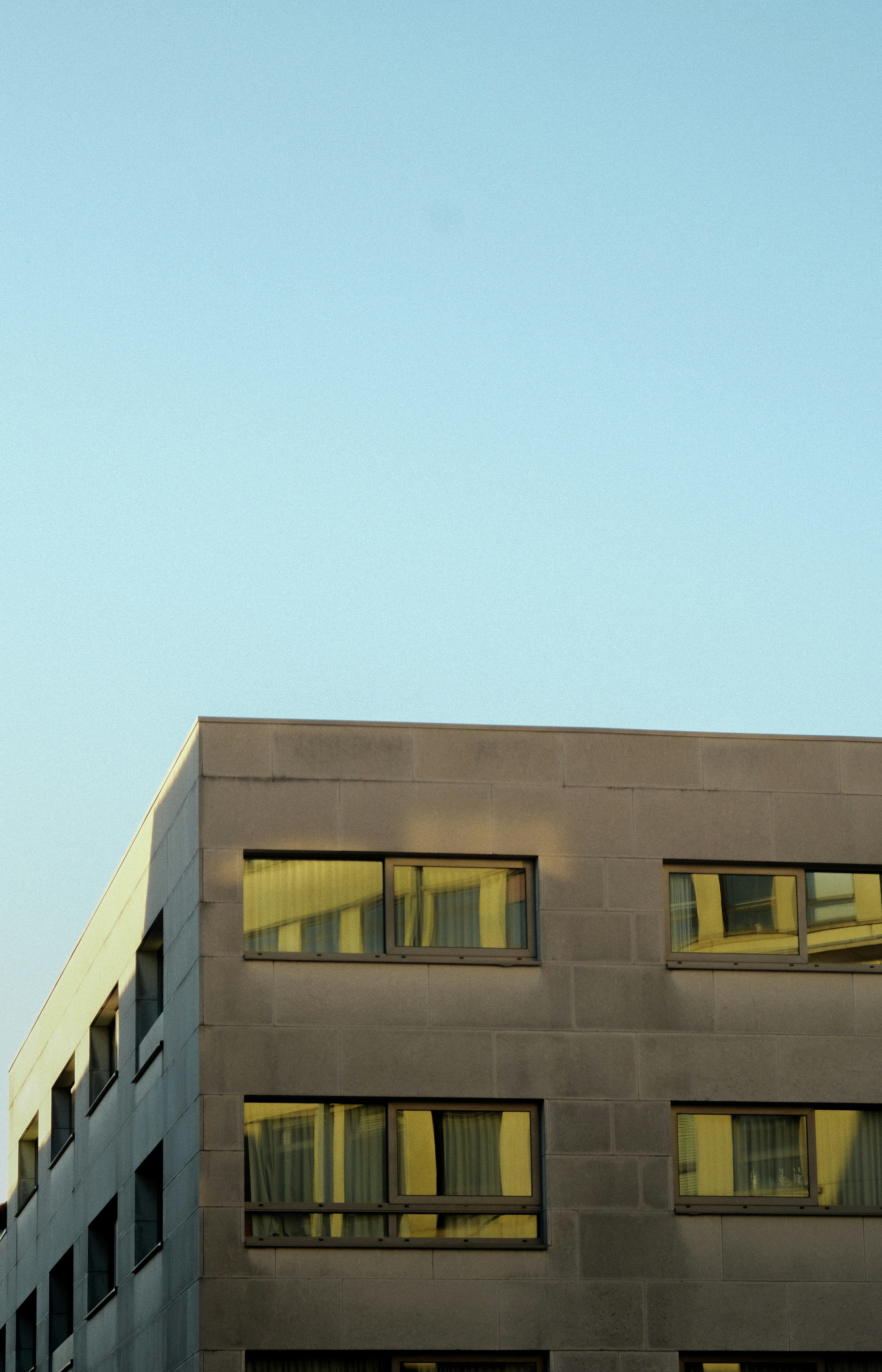 Modern building facade with angular design and reflective glass windows under a clear sky.