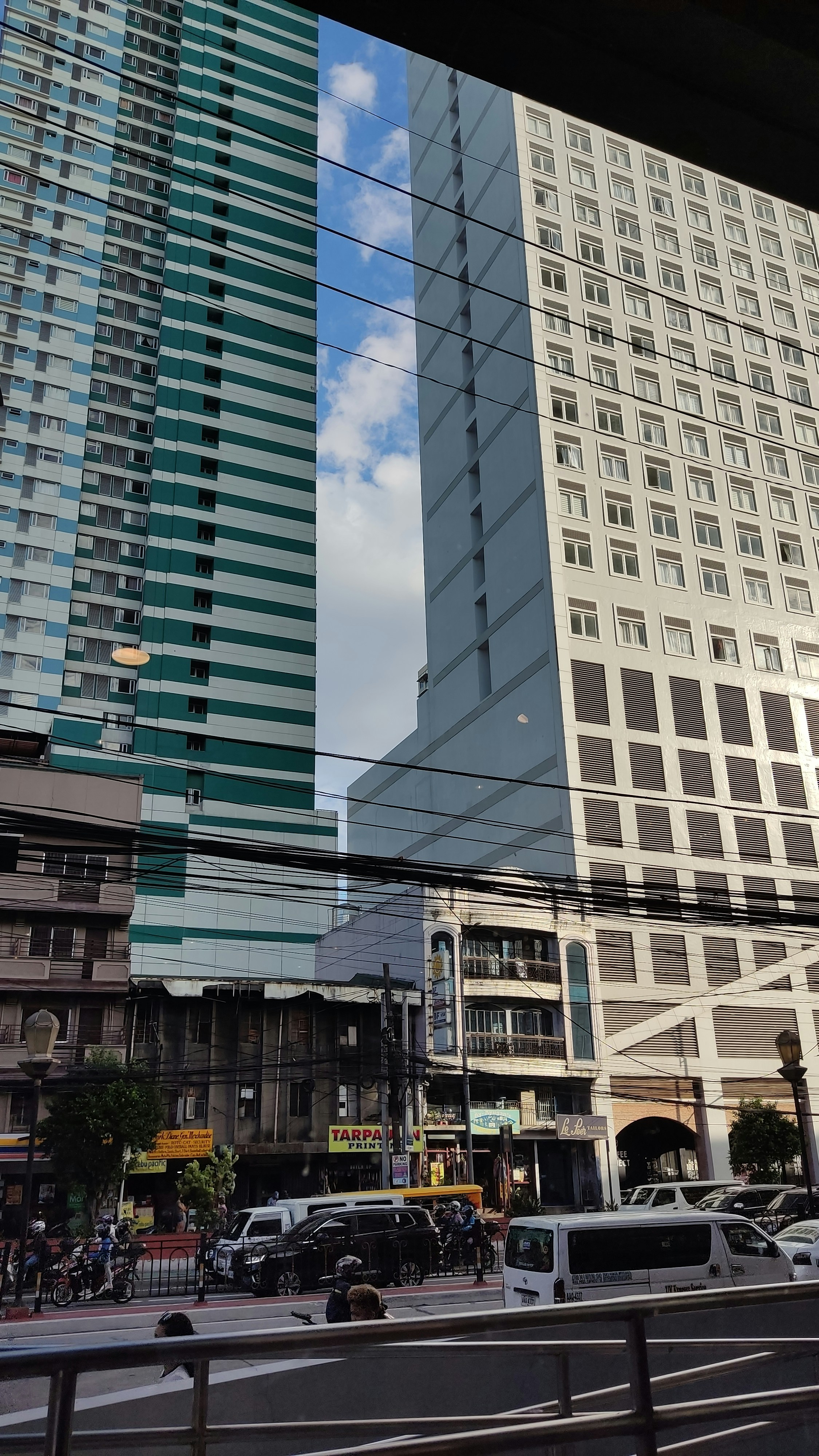 Modern high-rise buildings reflecting the sky, interspersed with bustling street activity below.