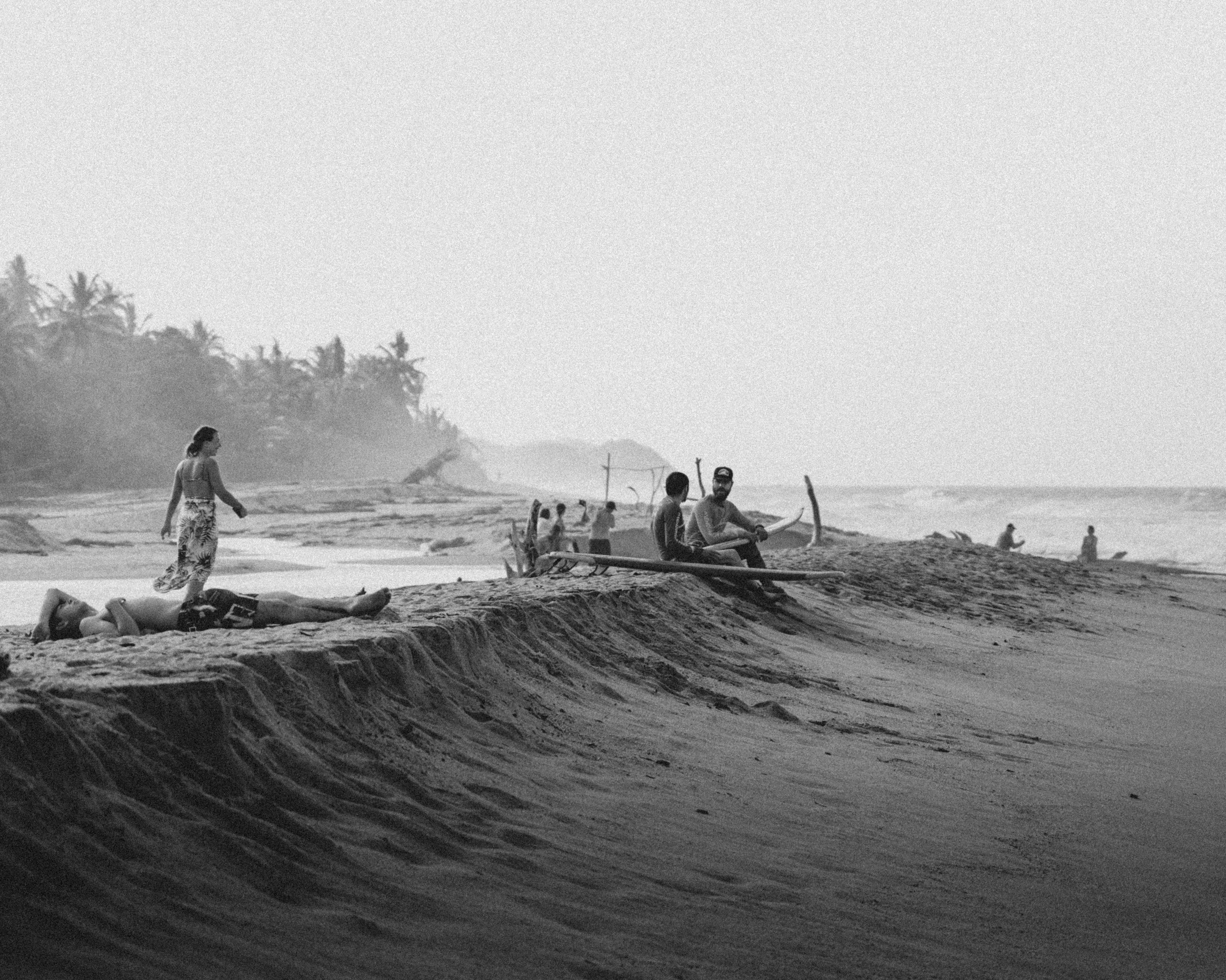 Monochrome Shoreline: Dunes, Fishermen, and a Quiet Boat